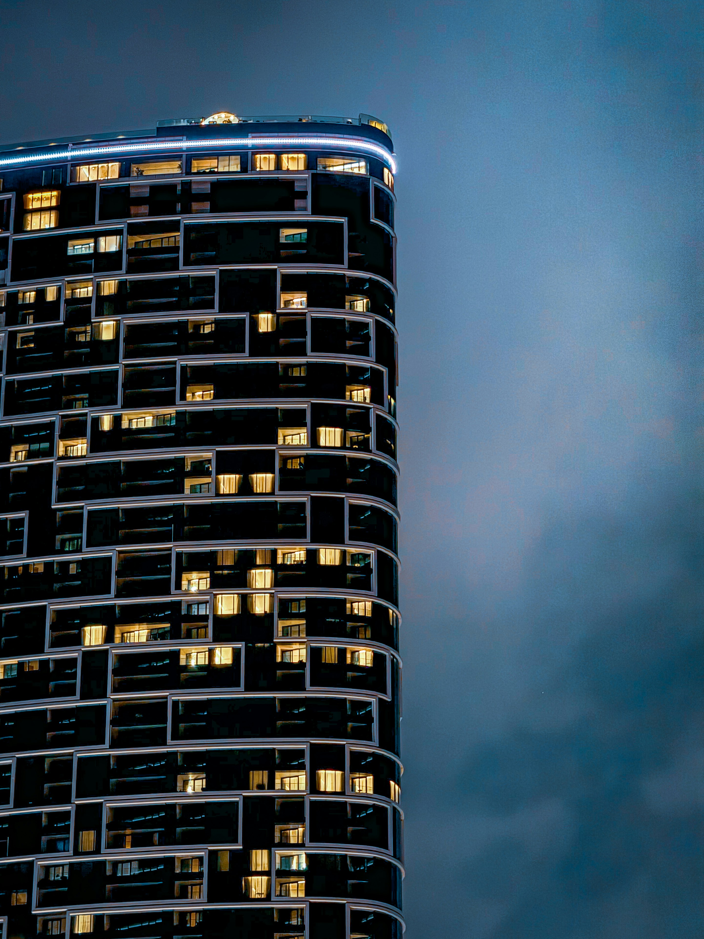 A very tall building with windows lit up at night photo – Free Blue ...