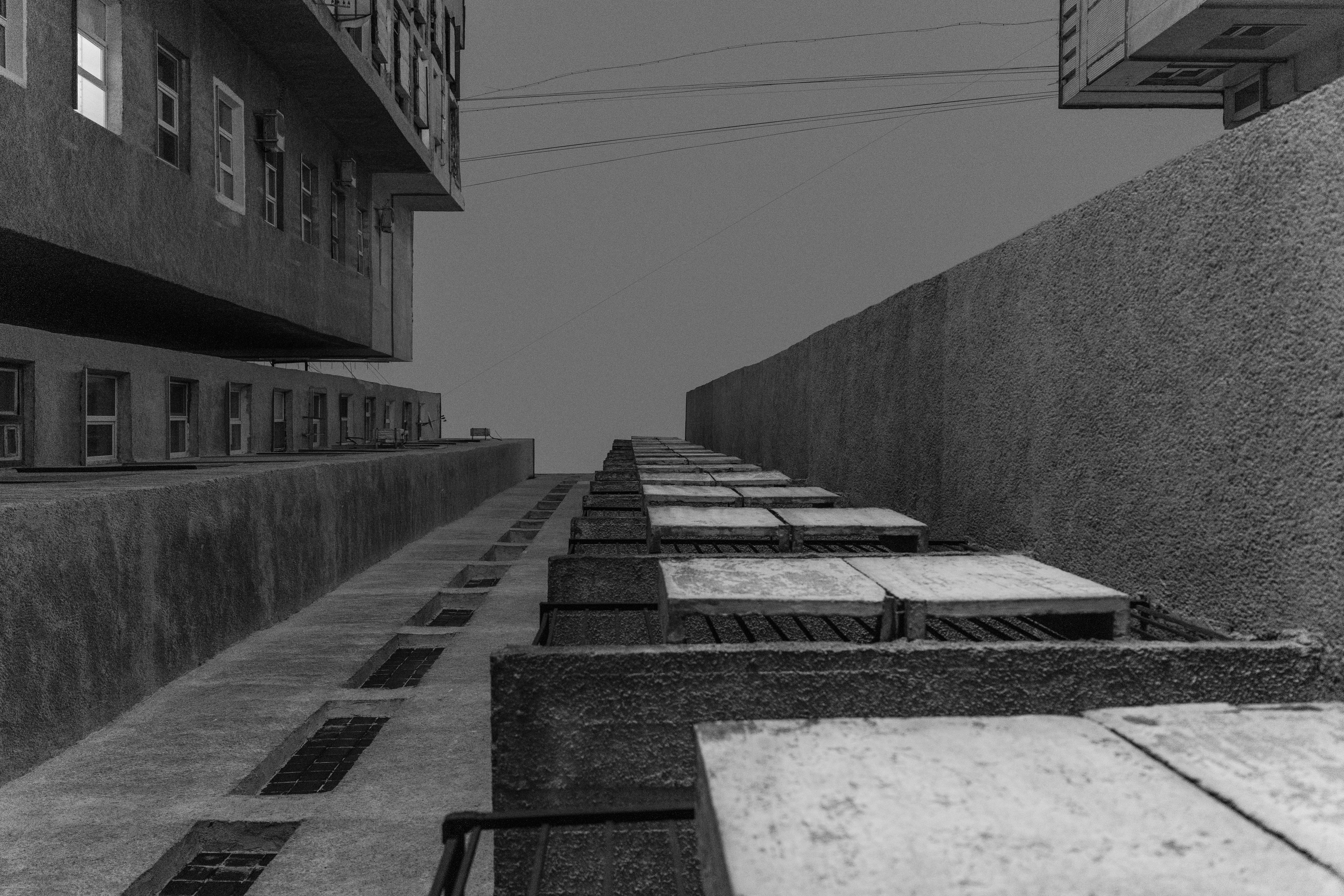 Abstract view of a narrow alleyway between towering concrete buildings, emphasizing architectural lines and textures.