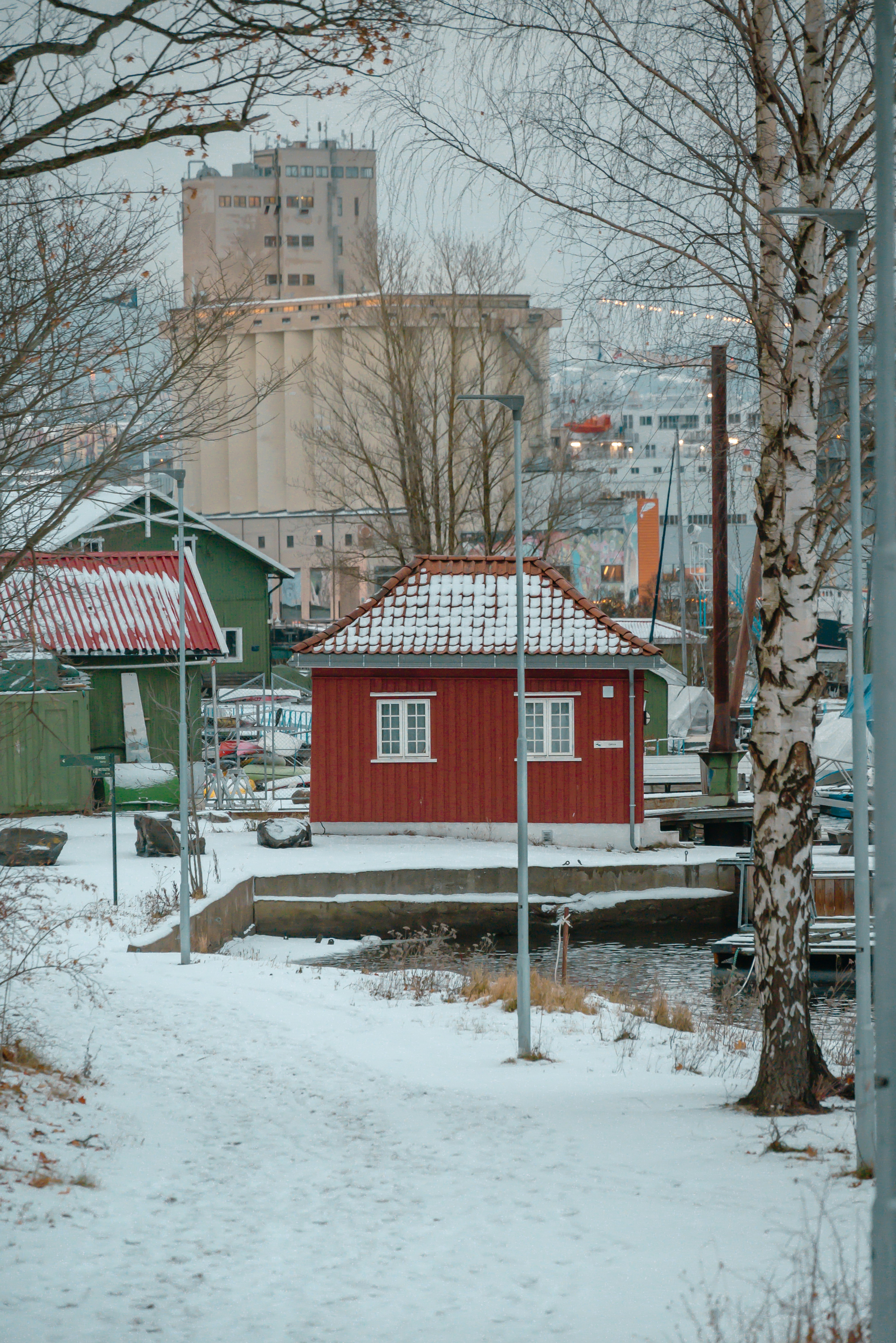 Red Cabin by a Snow-Blanketed Canal in an Urban Winter Scene