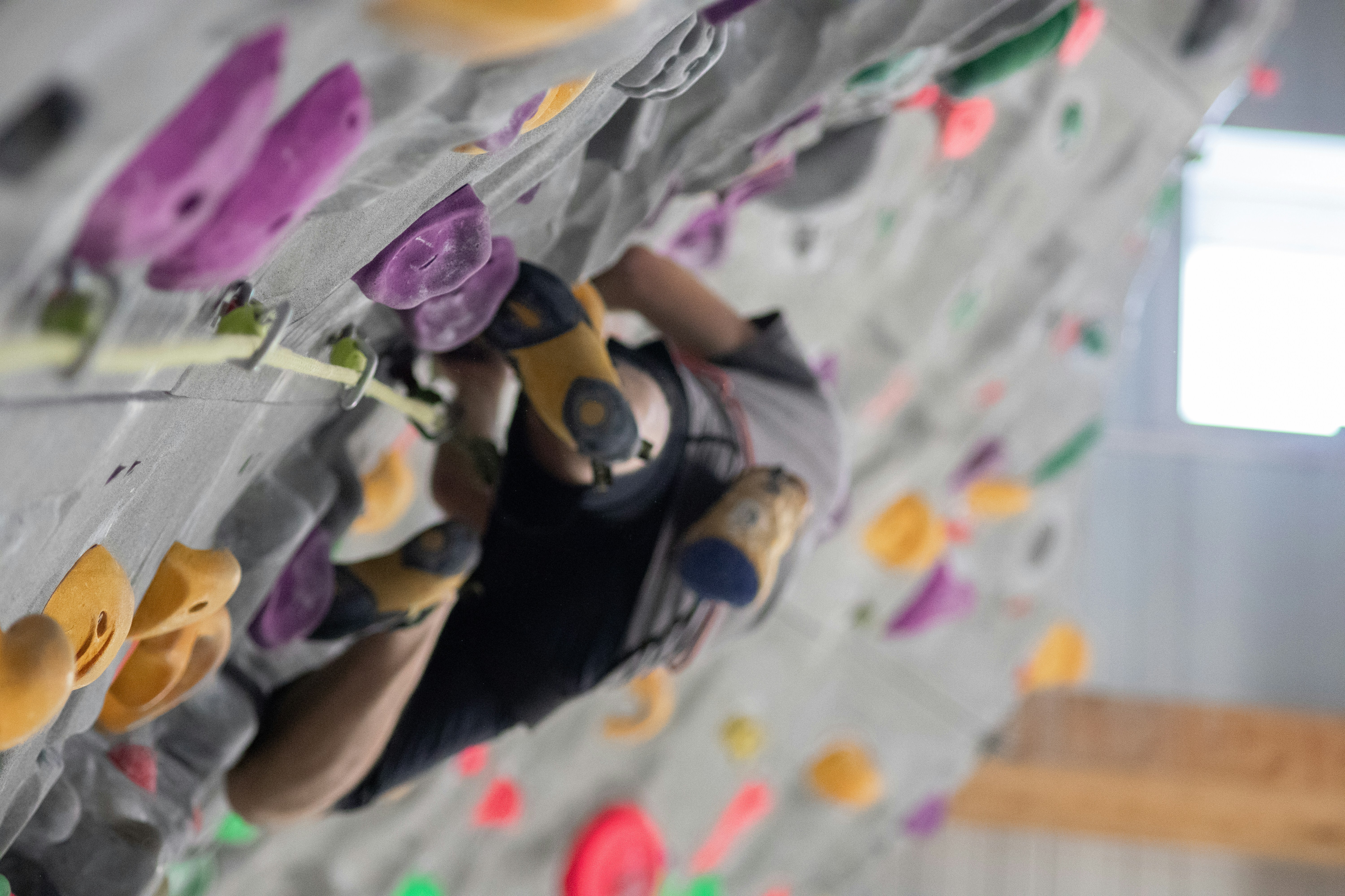 Climber navigating colorful holds on an indoor rock wall, showcasing skill and focus.