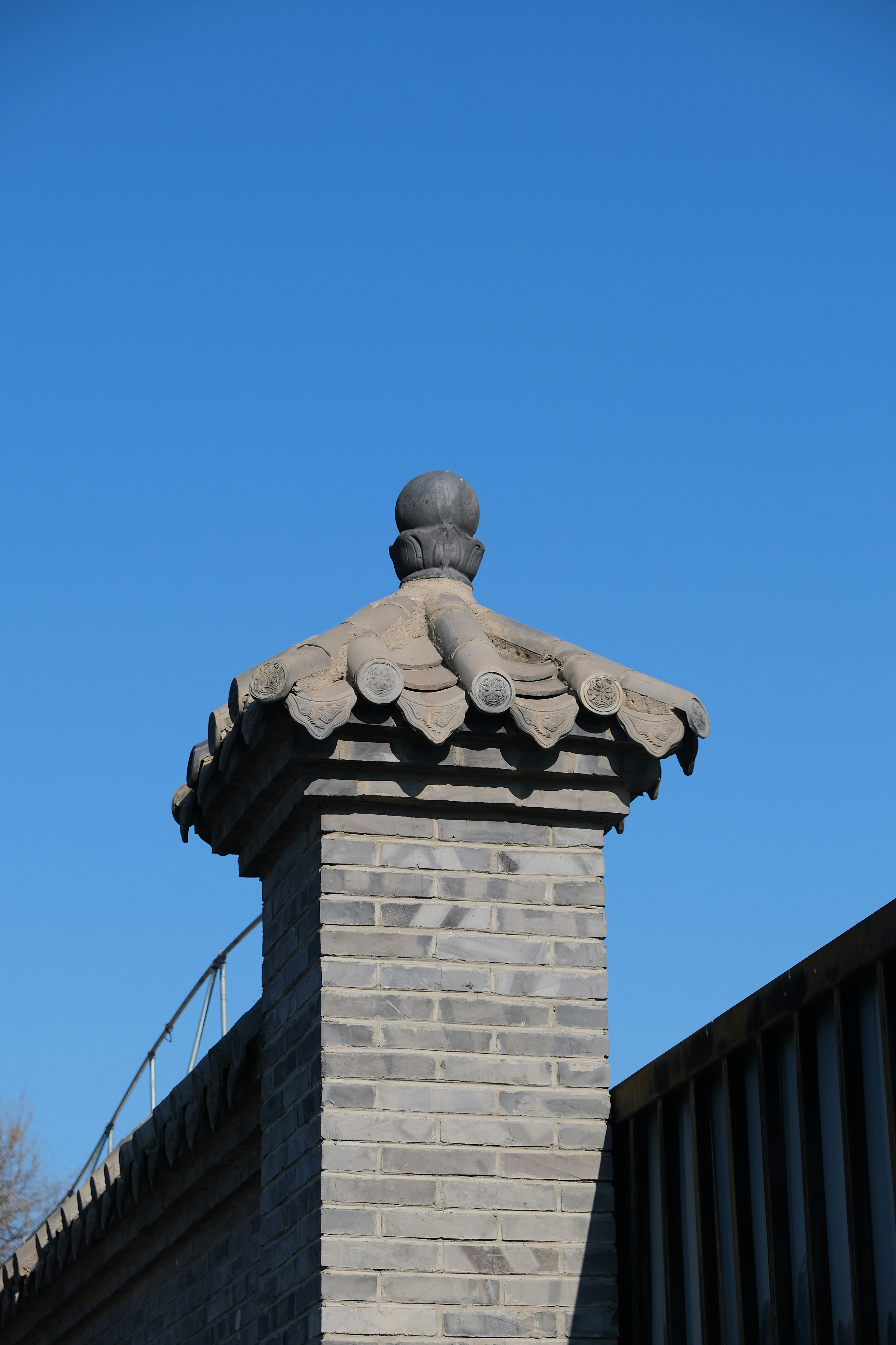 Tile-Crowned Finial on a Brick Pillar Under a Cerulean Sky