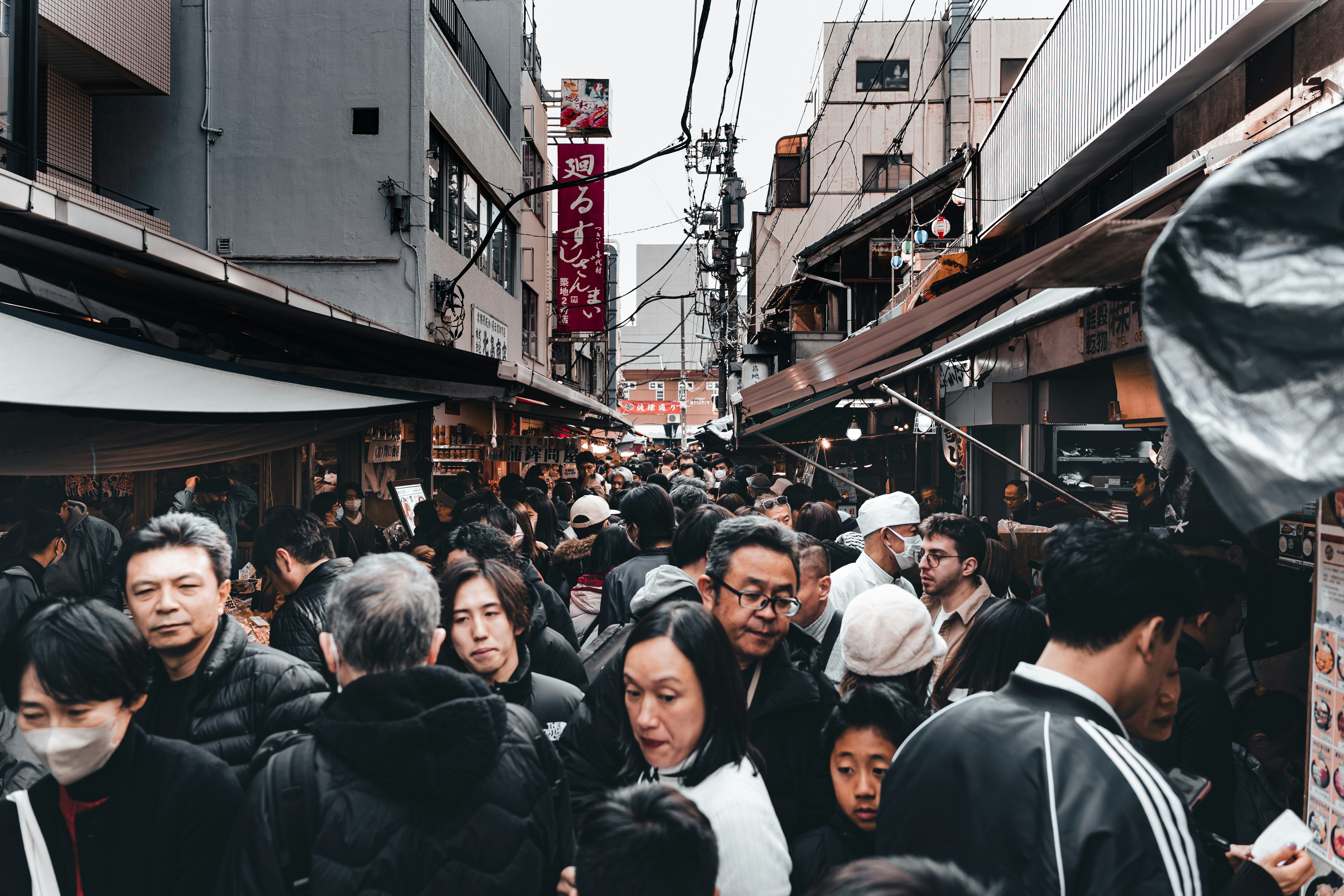 A crowd of people walking down a street next to tall buildings photo ...