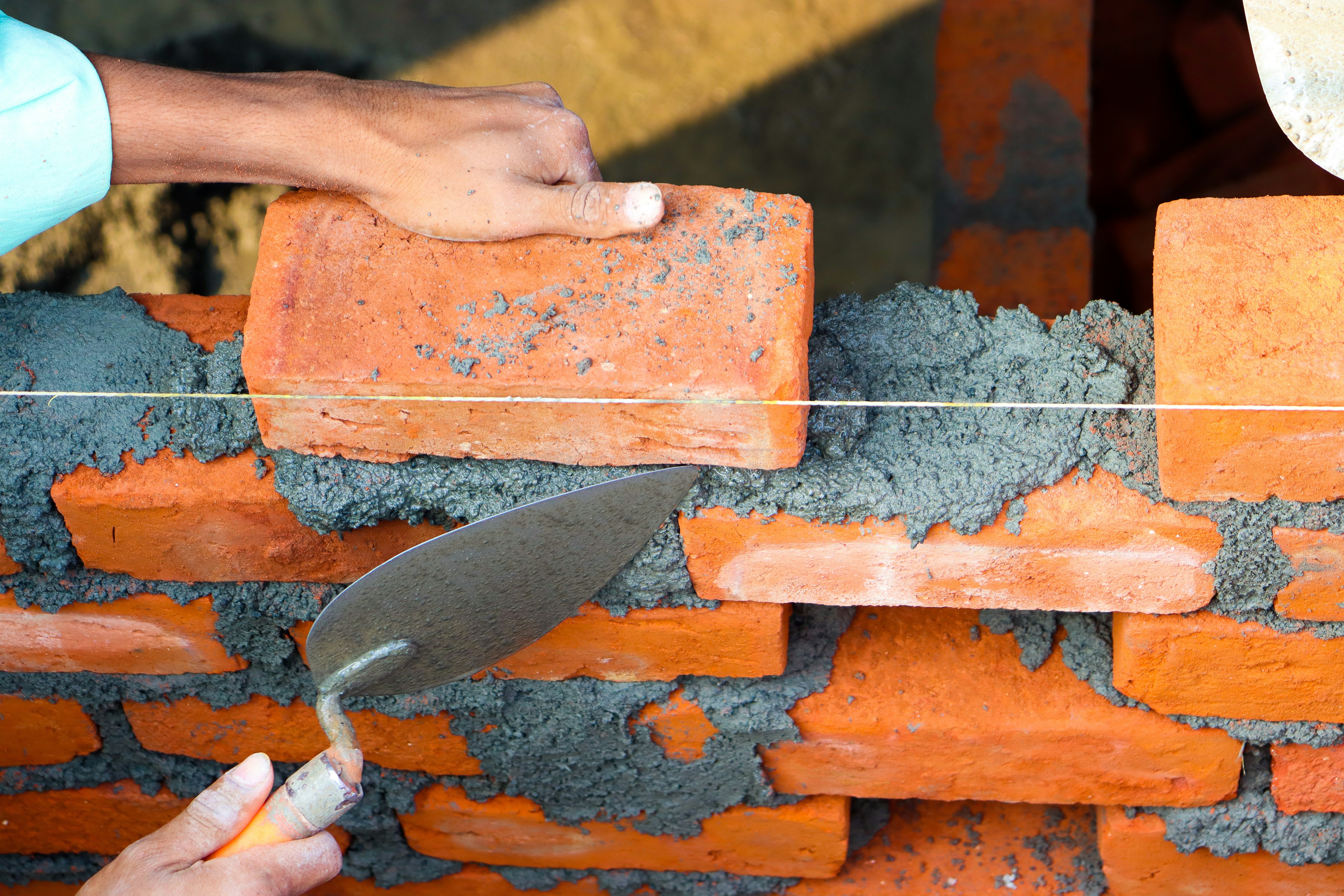 A brick wall being built with a pair of hands photo – Free Brick Image ...