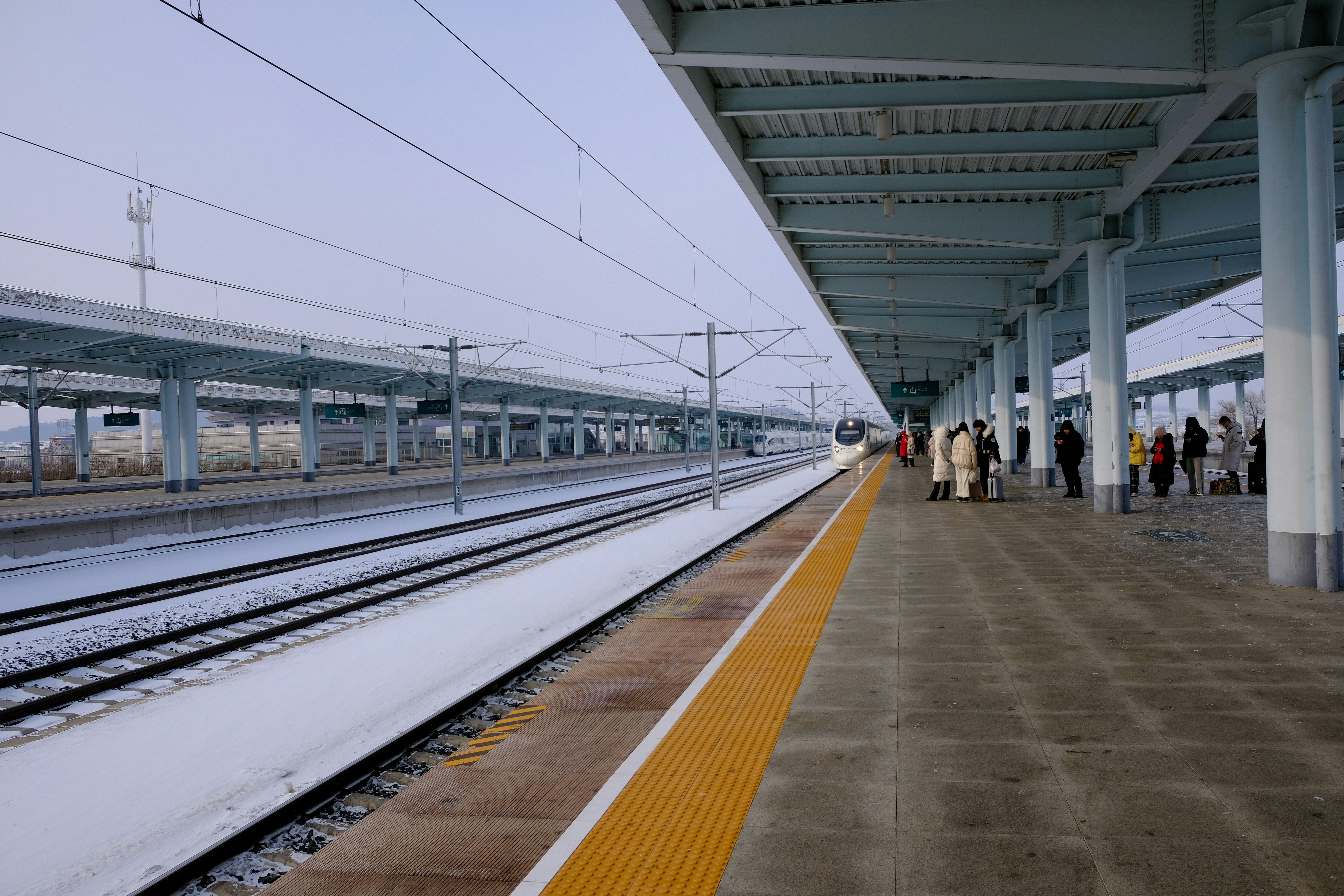 A group of people waiting for a train at a train station photo – Free ...