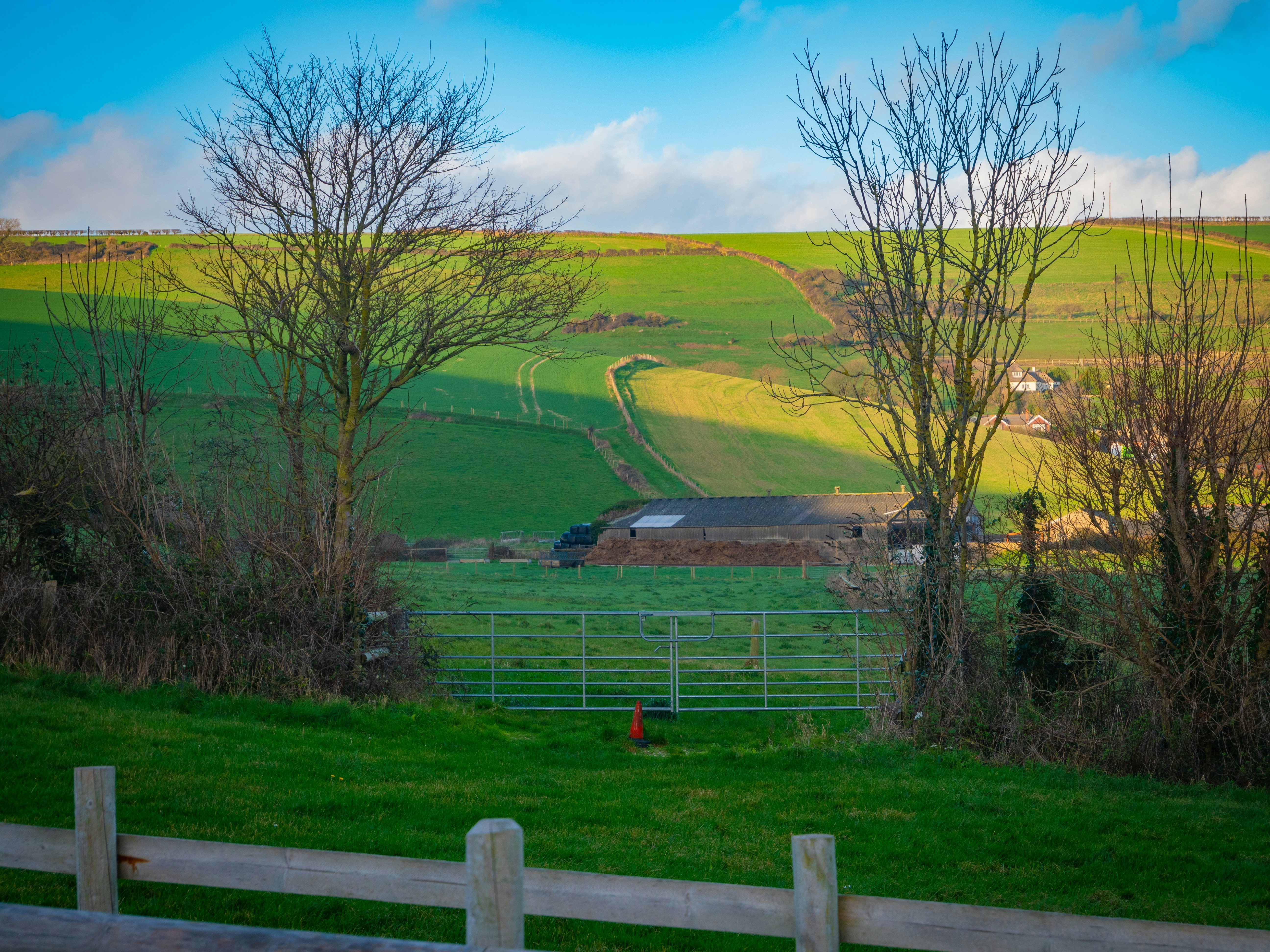 Distant Shed Amid Patchwork Hills Under Open Sky