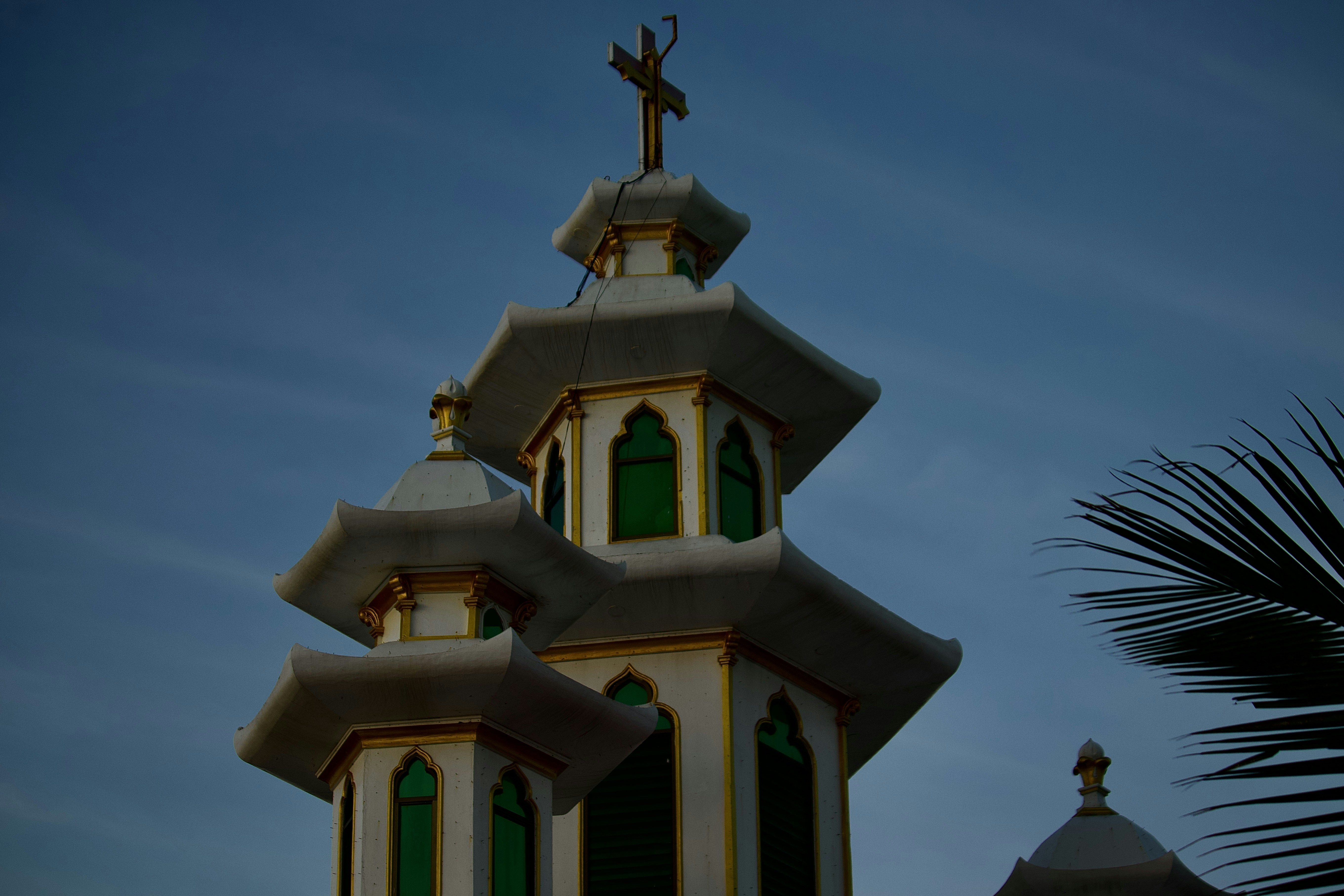 Cross-Topped Tiered Shrine Against a Calm Blue Sky