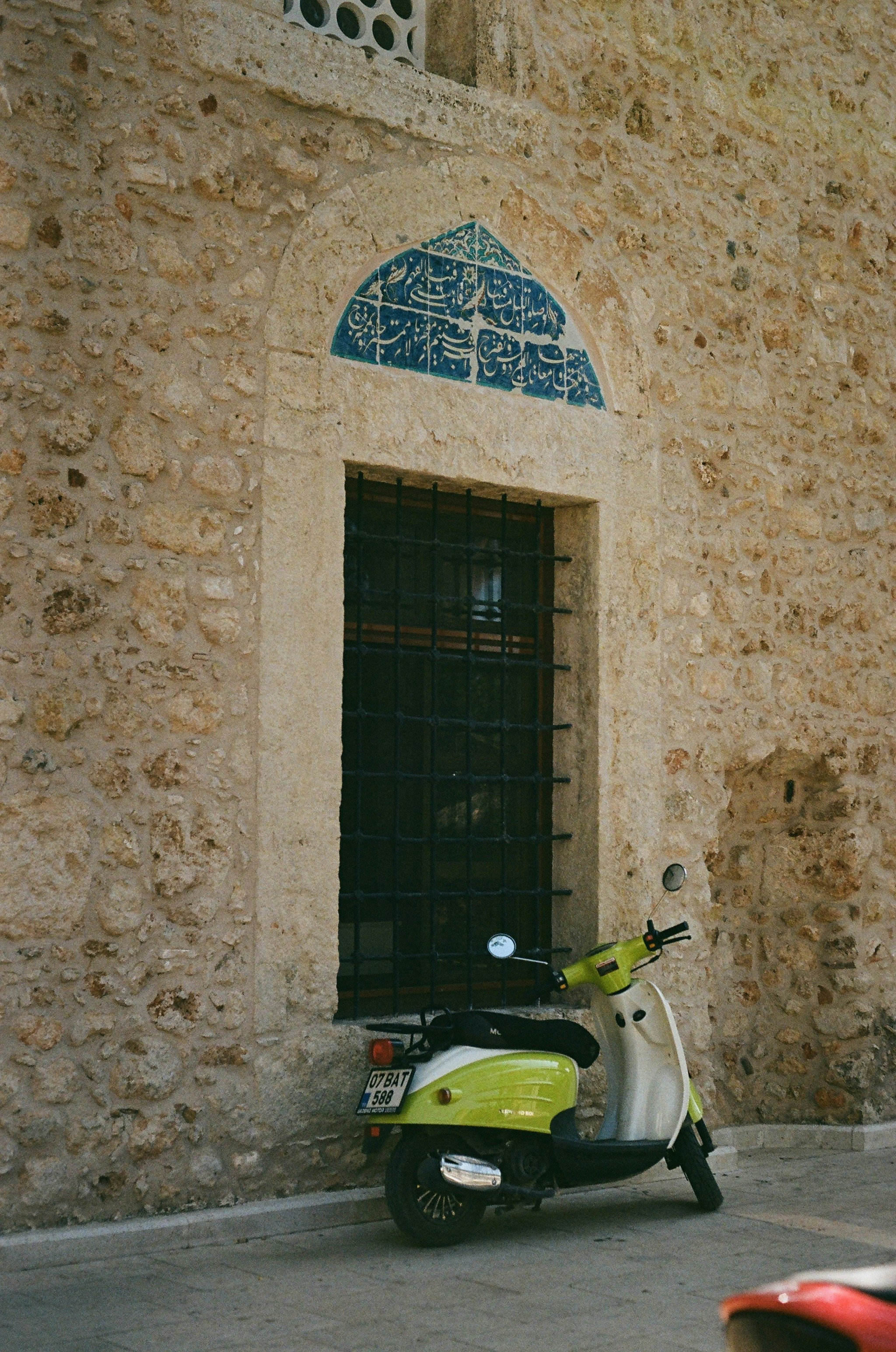 Green Vespa by the stone archway