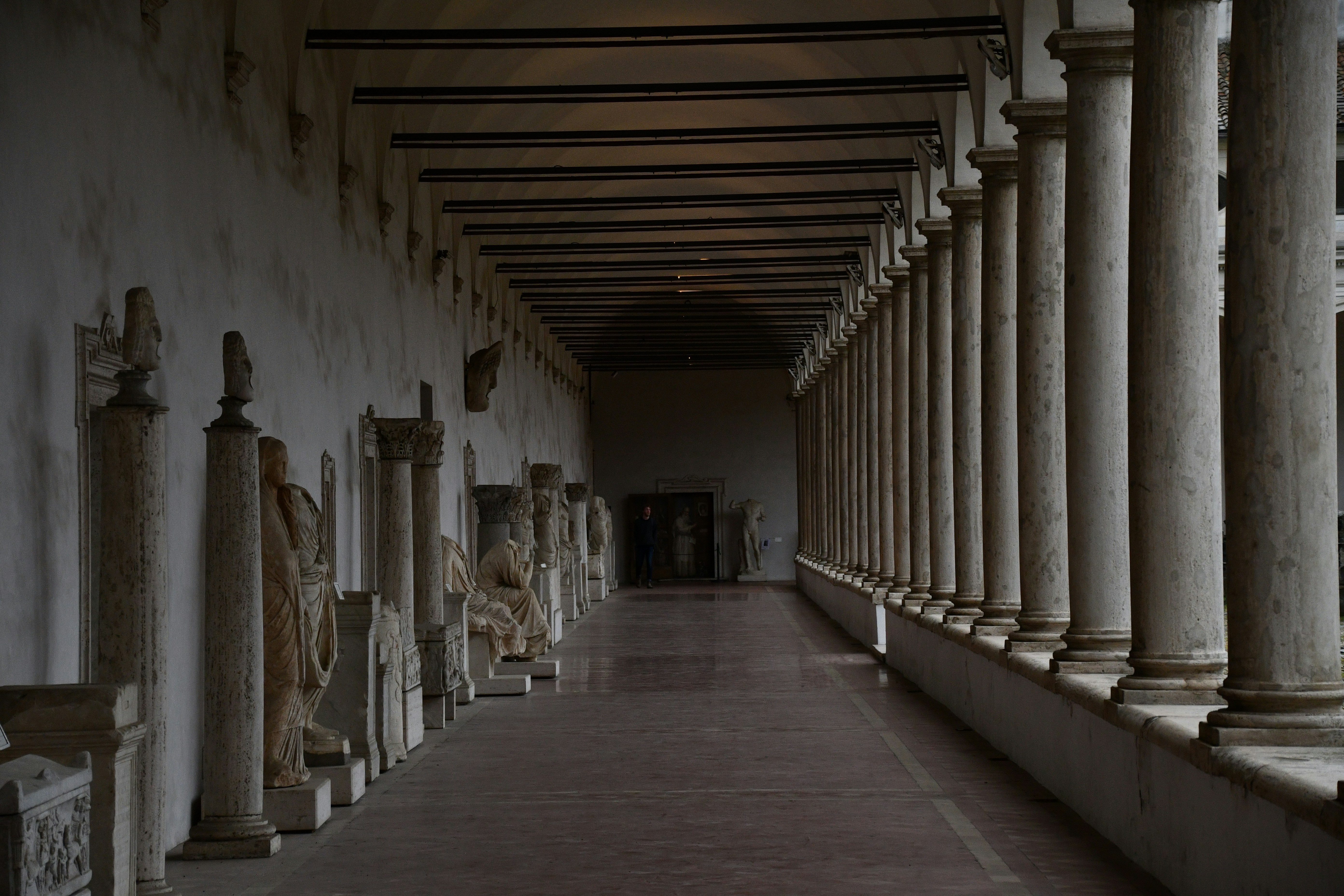 A long hallway lined with columns and statues photo – Free Rome Image ...