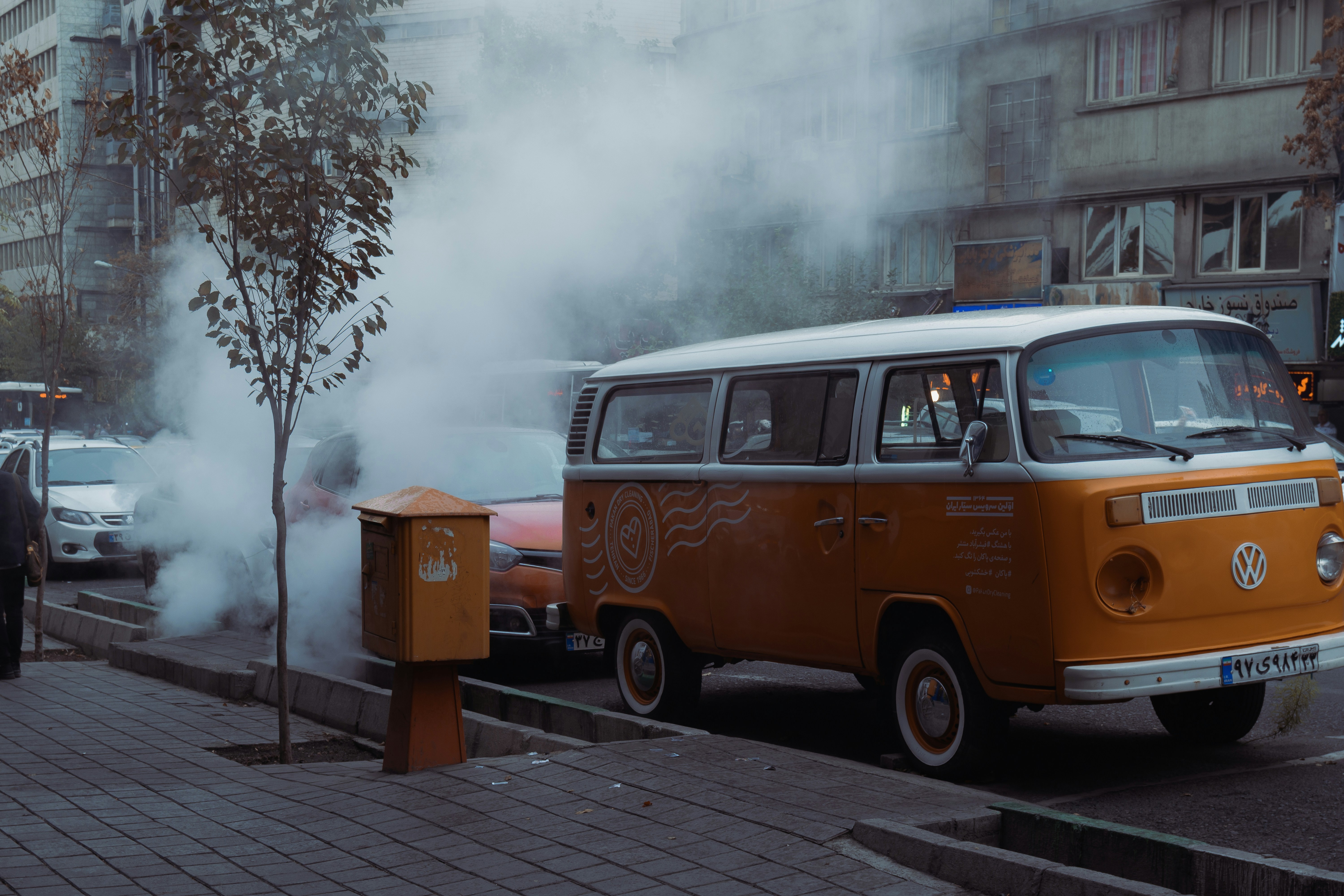 Haze-tinged Transit: A Vintage VW Van on a Smoke-Washed City Street