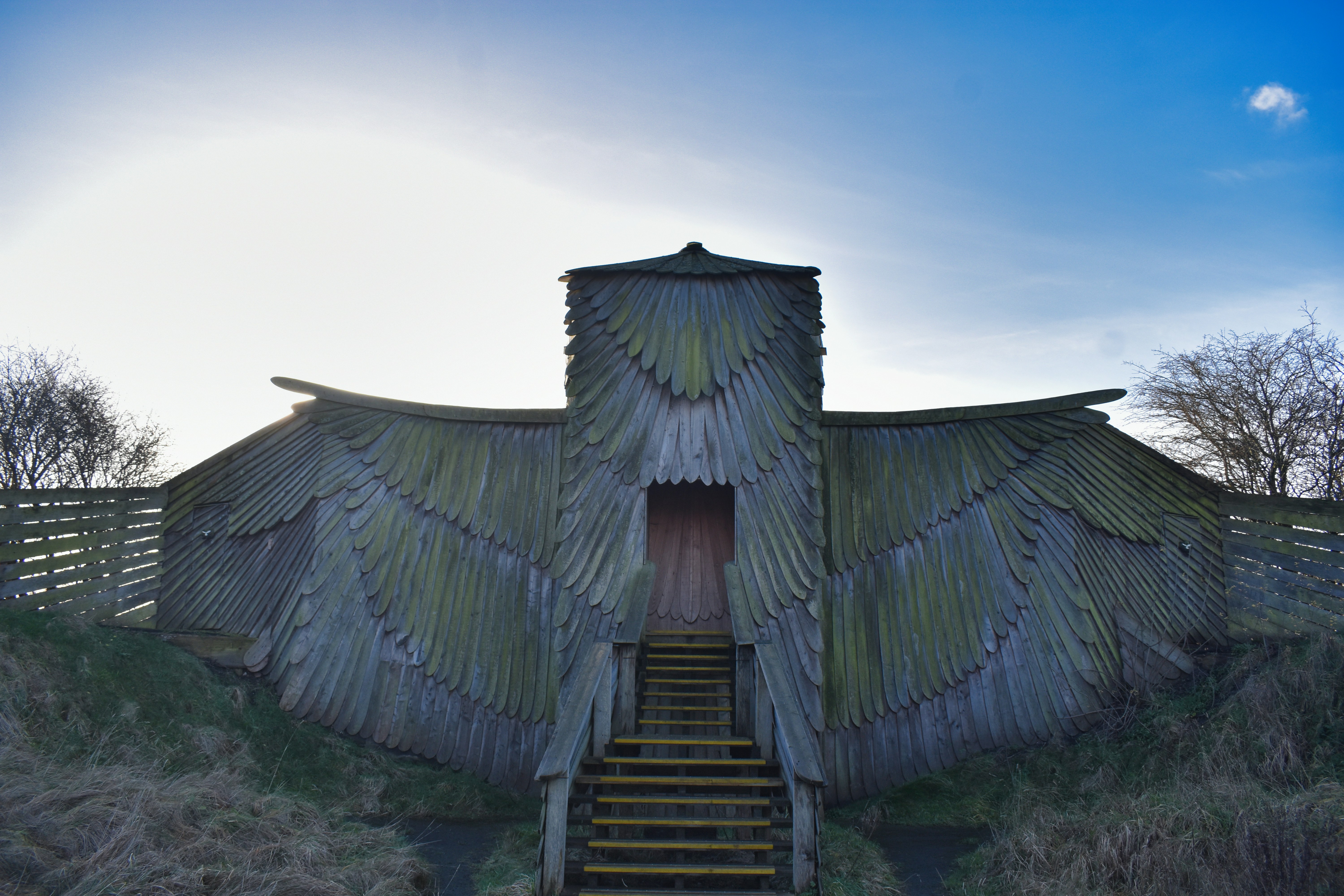 a wooden structure with a large bird wing on top of it