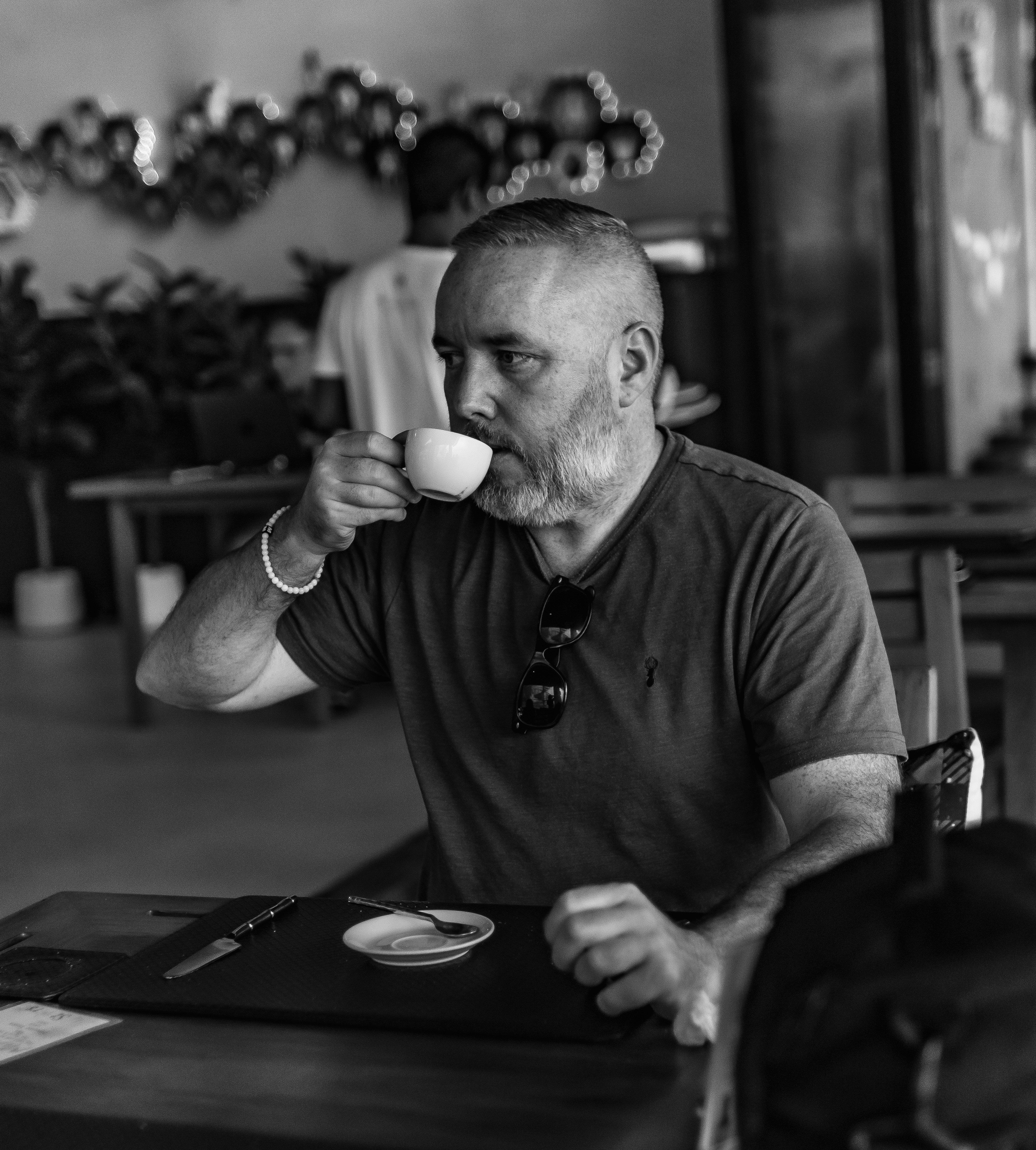 Monochrome Moment: A Man Delights in Espresso Beneath Subtle Café Lights