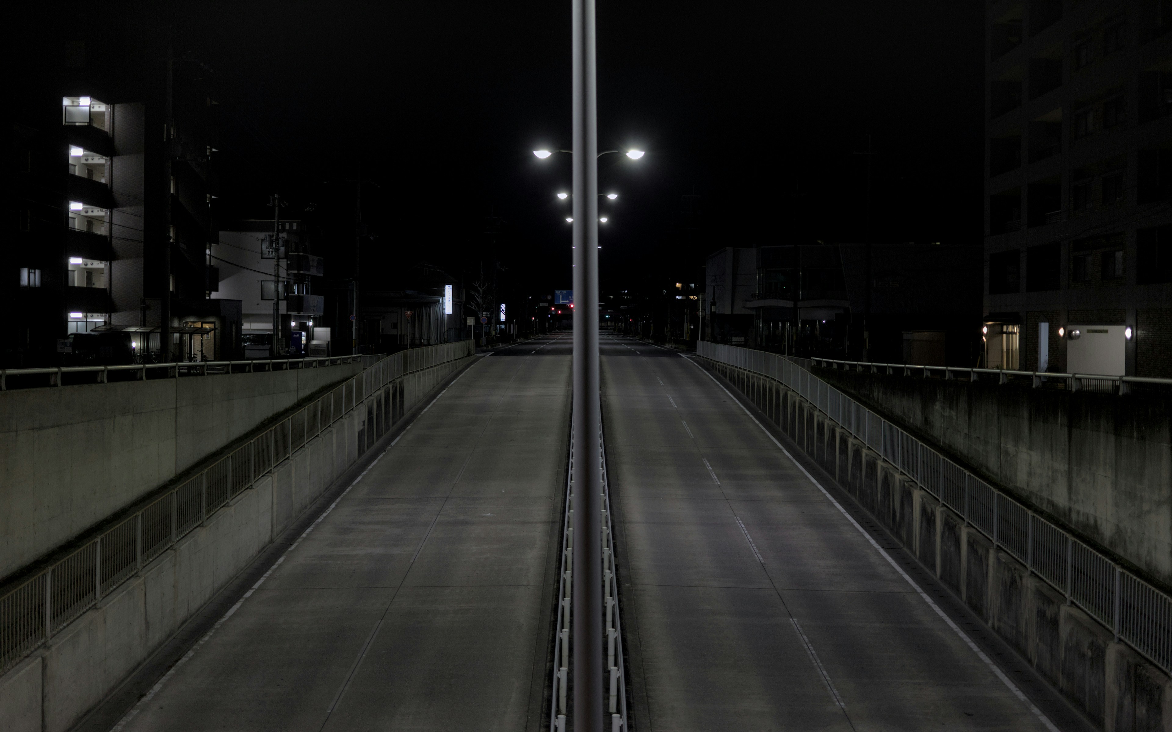 A night-time look down the center of a four-lane street and underpass in Kyoto's Katsura ward. No cars, no people. 2024-01-01 @ XPC8+W6HJulien