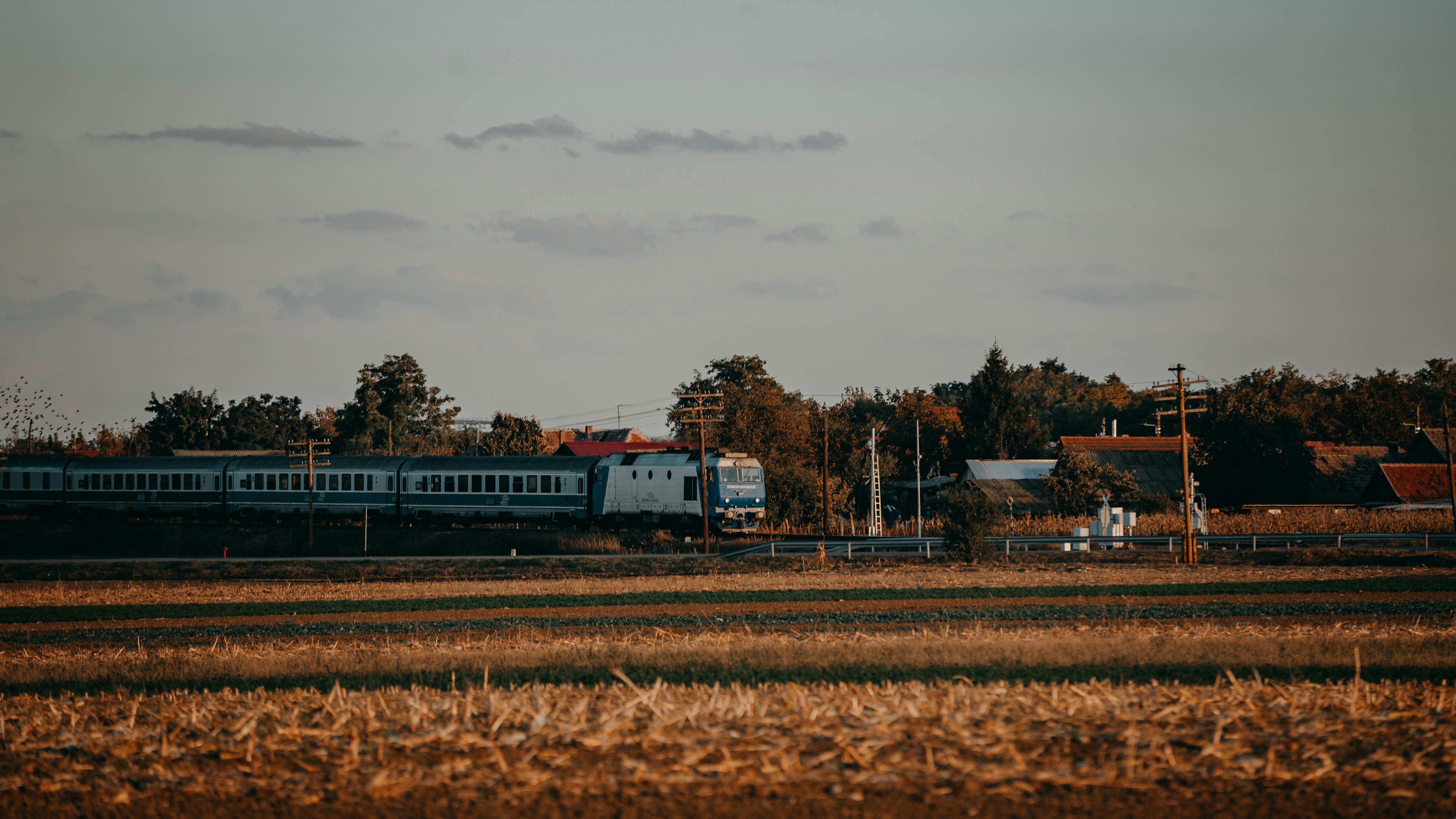 A train traveling through a rural countryside under a cloudy sky photo ...