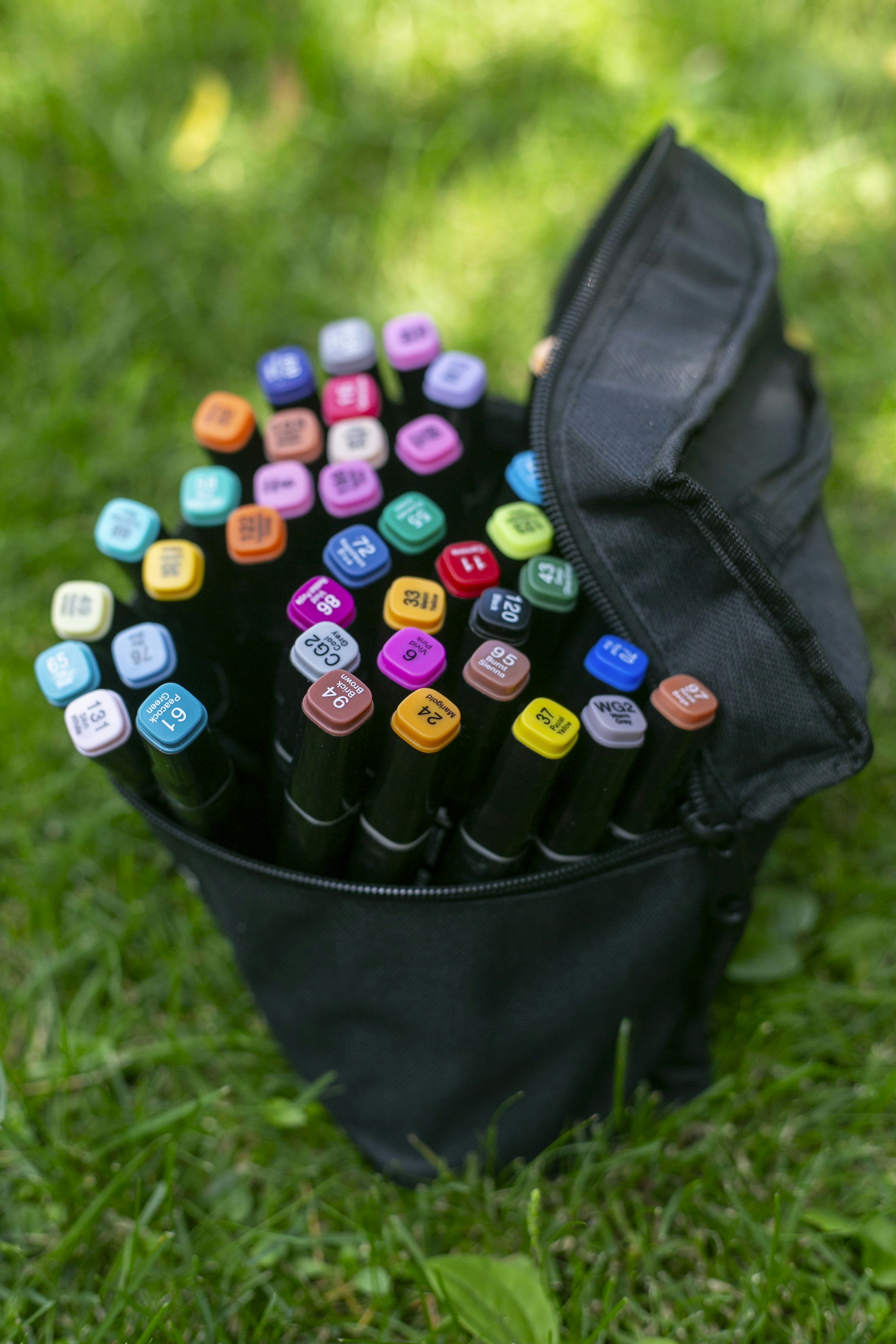 A bunch of markers sitting in a bag on the grass photo – Free Bag Image ...