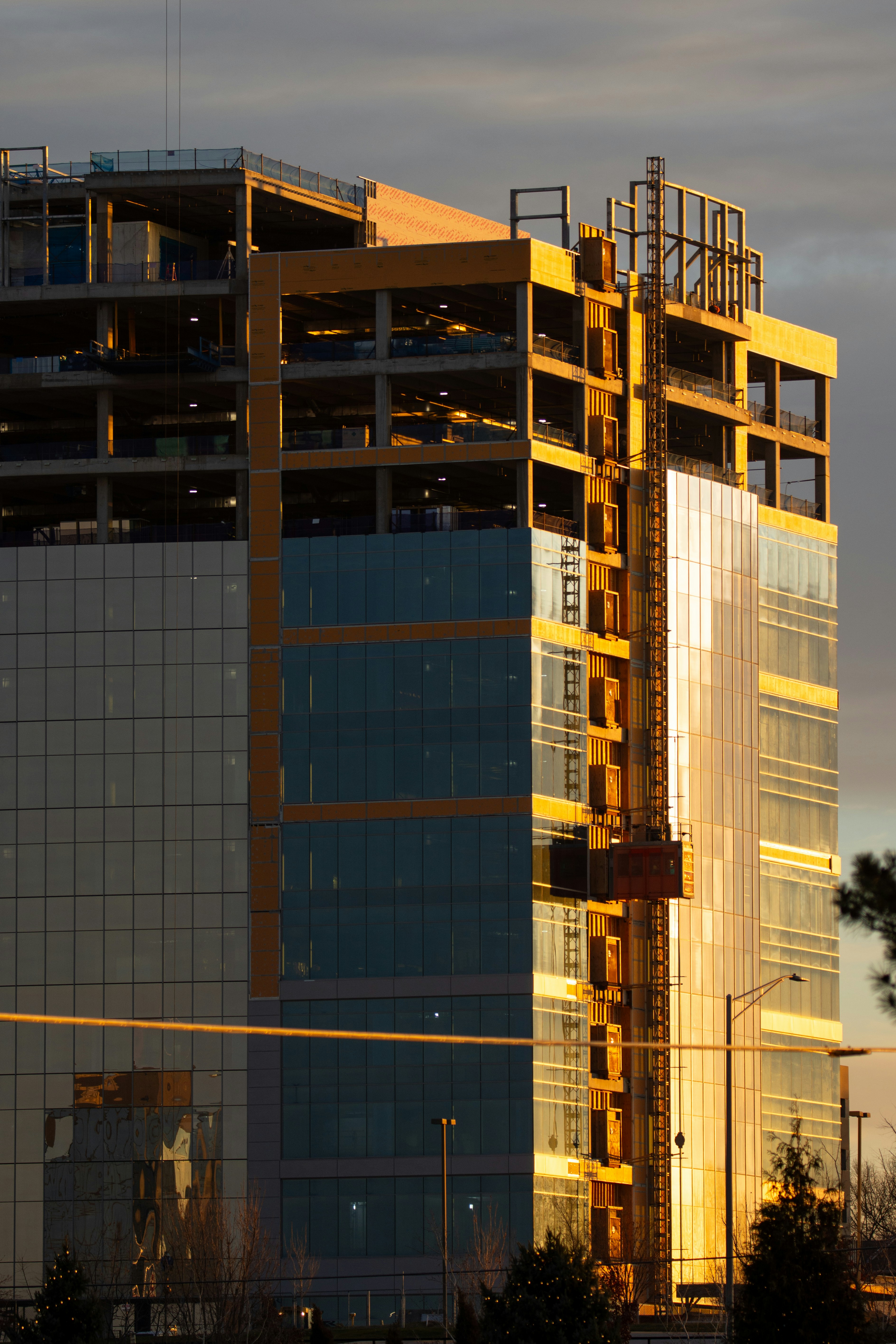 Golden Hour Skeleton: Glass-Fronted Tower Under Construction