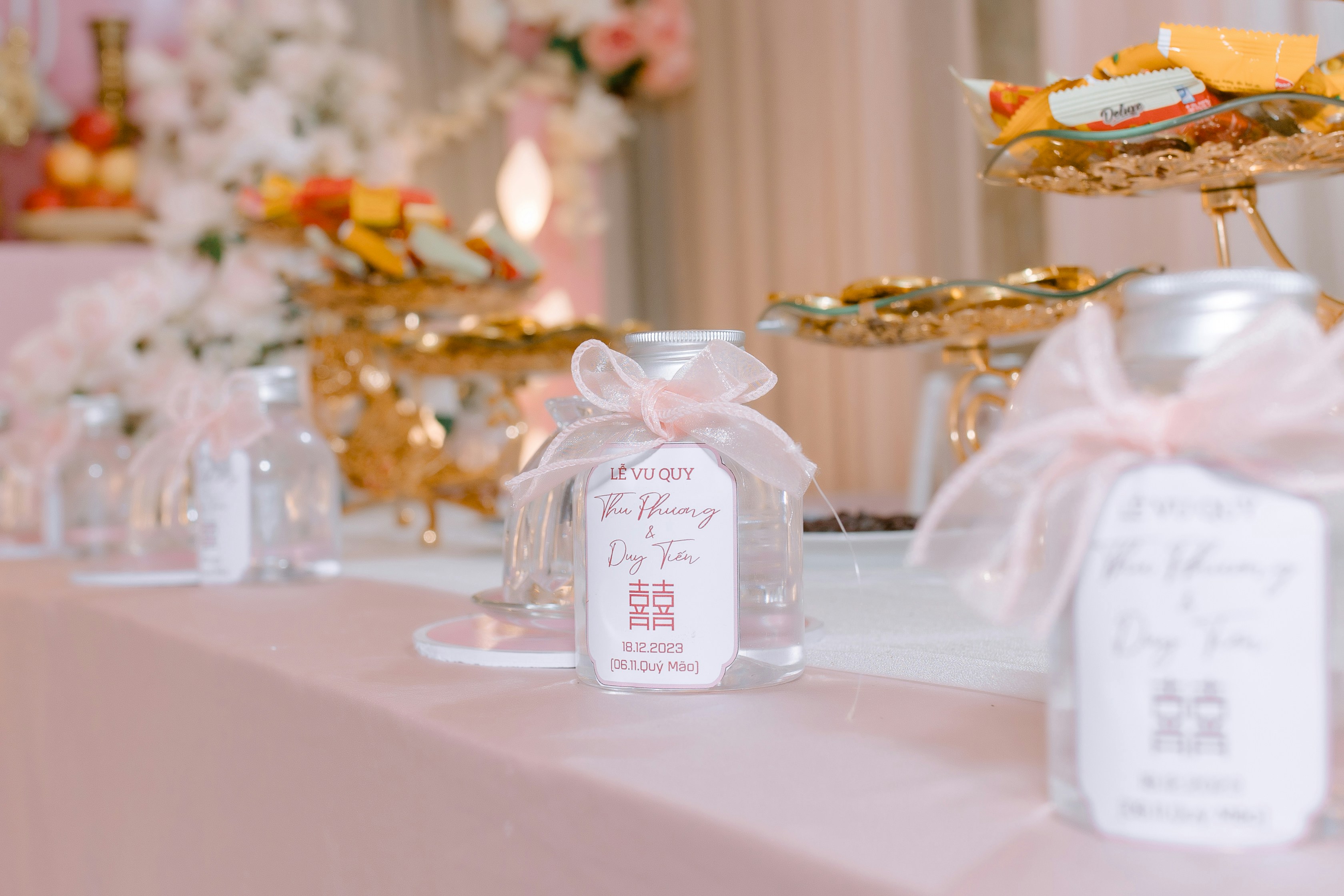 Glass jars and tiered treats on a pastel reception table fade into soft bokeh