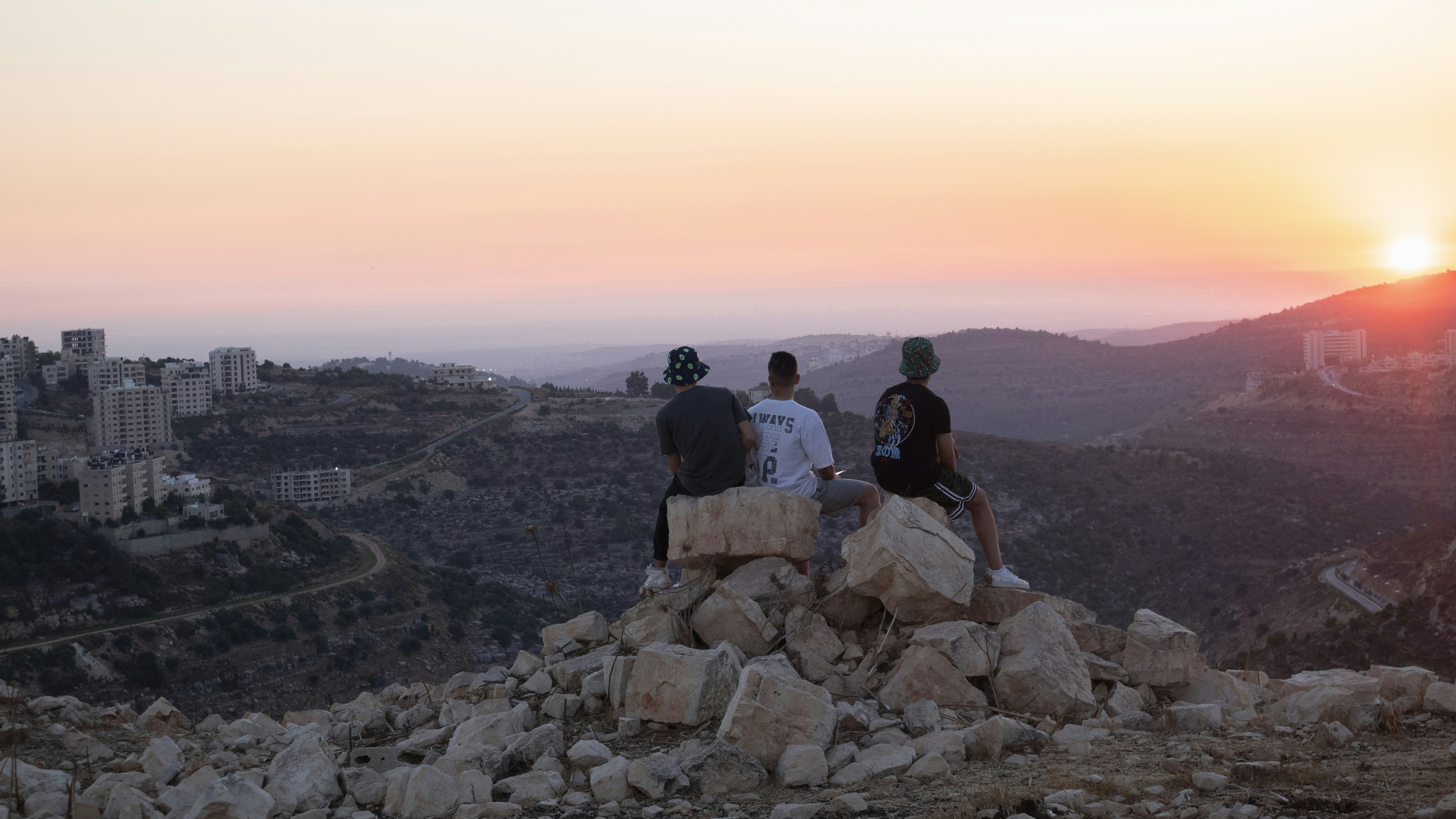 A group of people sitting on top of a pile of rocks photo – Free ...