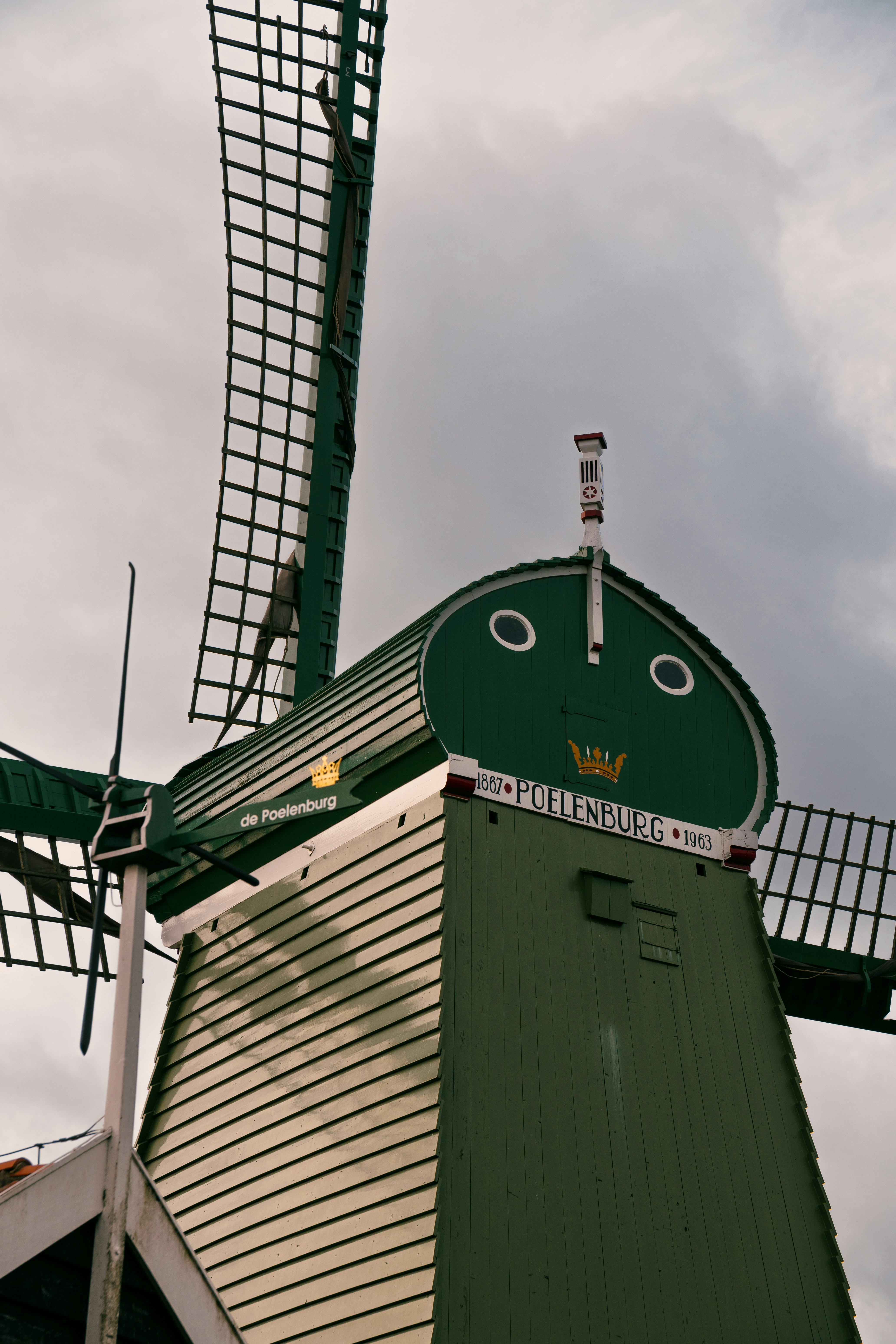 Emerald Windmill Crowned by Lattice Sails Against a Gloomy Sky