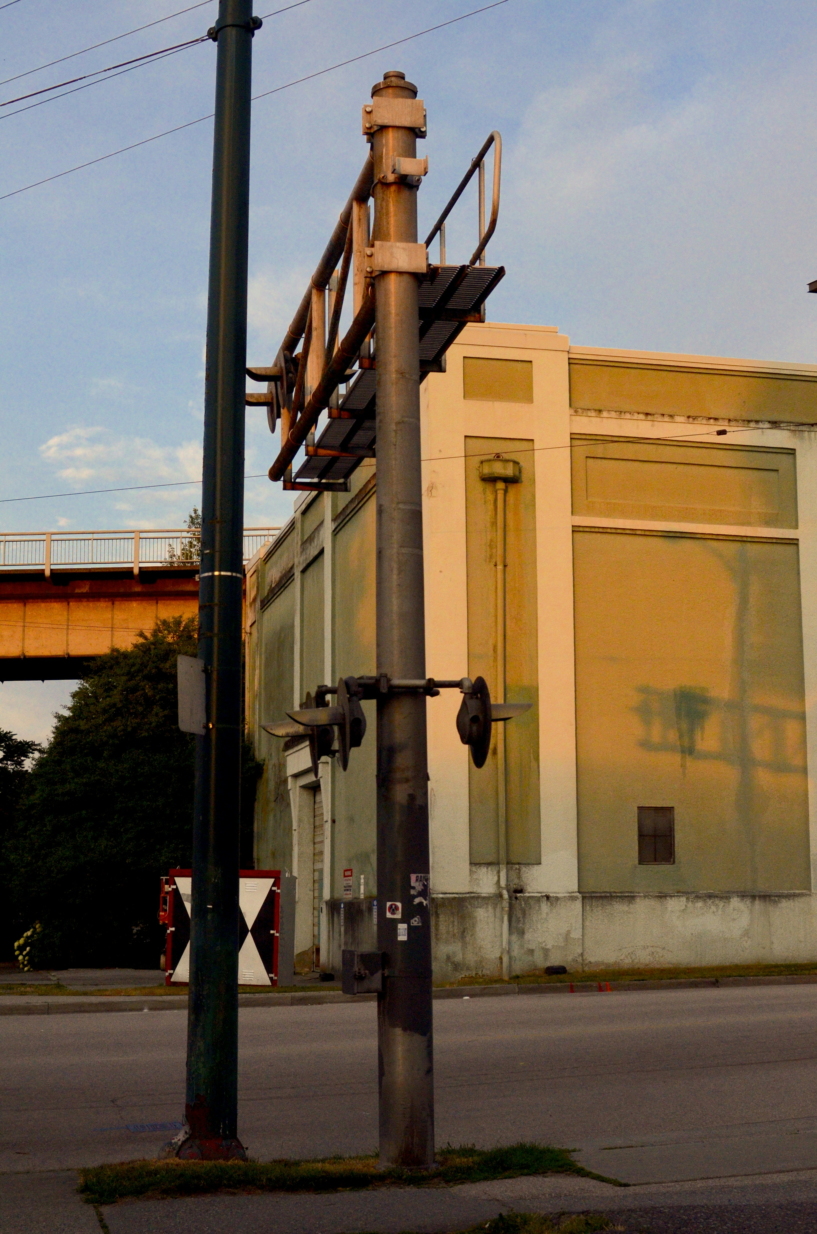 Sentinel on the Street: A Weathered Pole Framed by a Quiet Industrial Facade