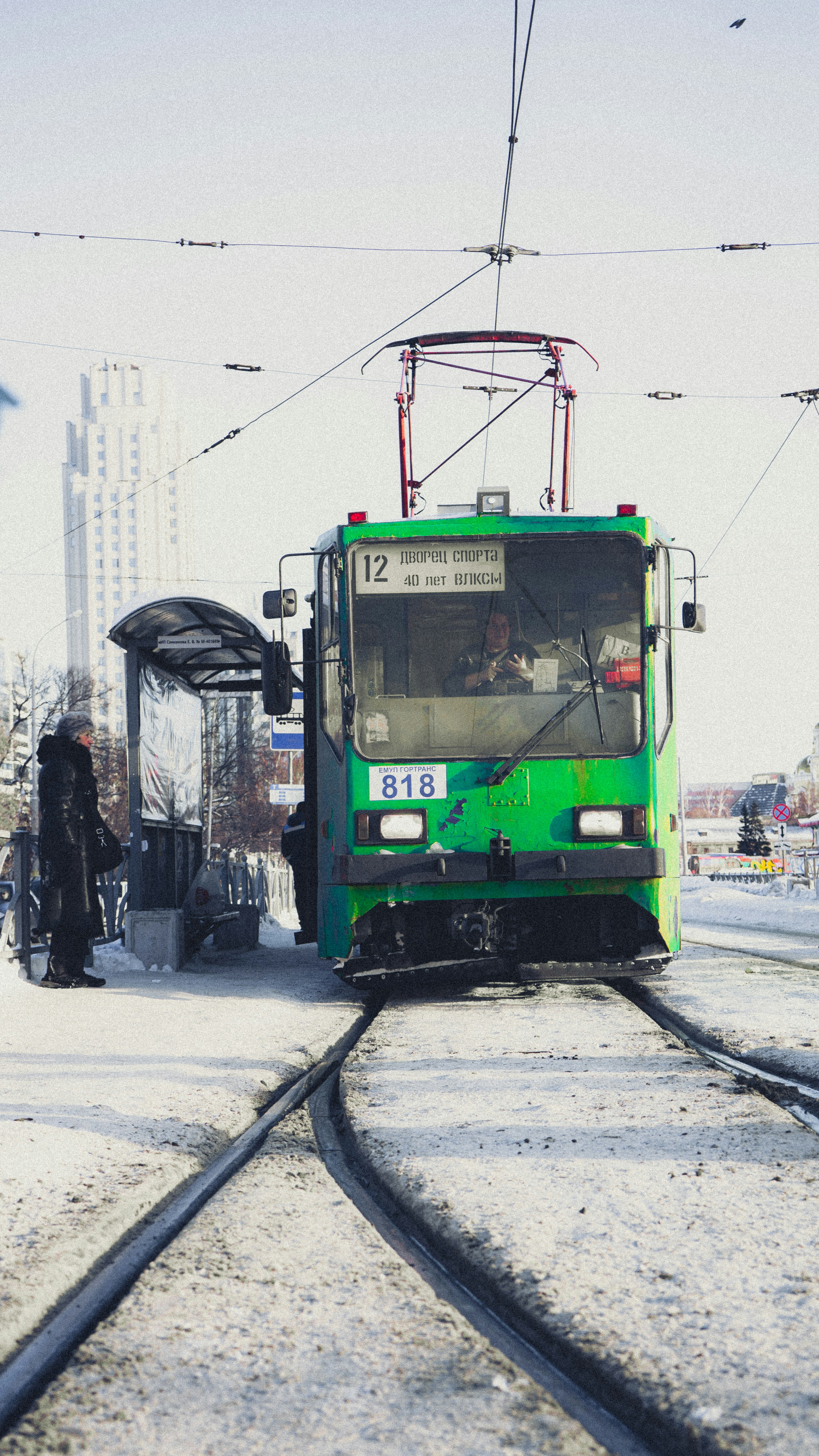 A green trolley car on a snowy train track photo – Free Woman Image on ...