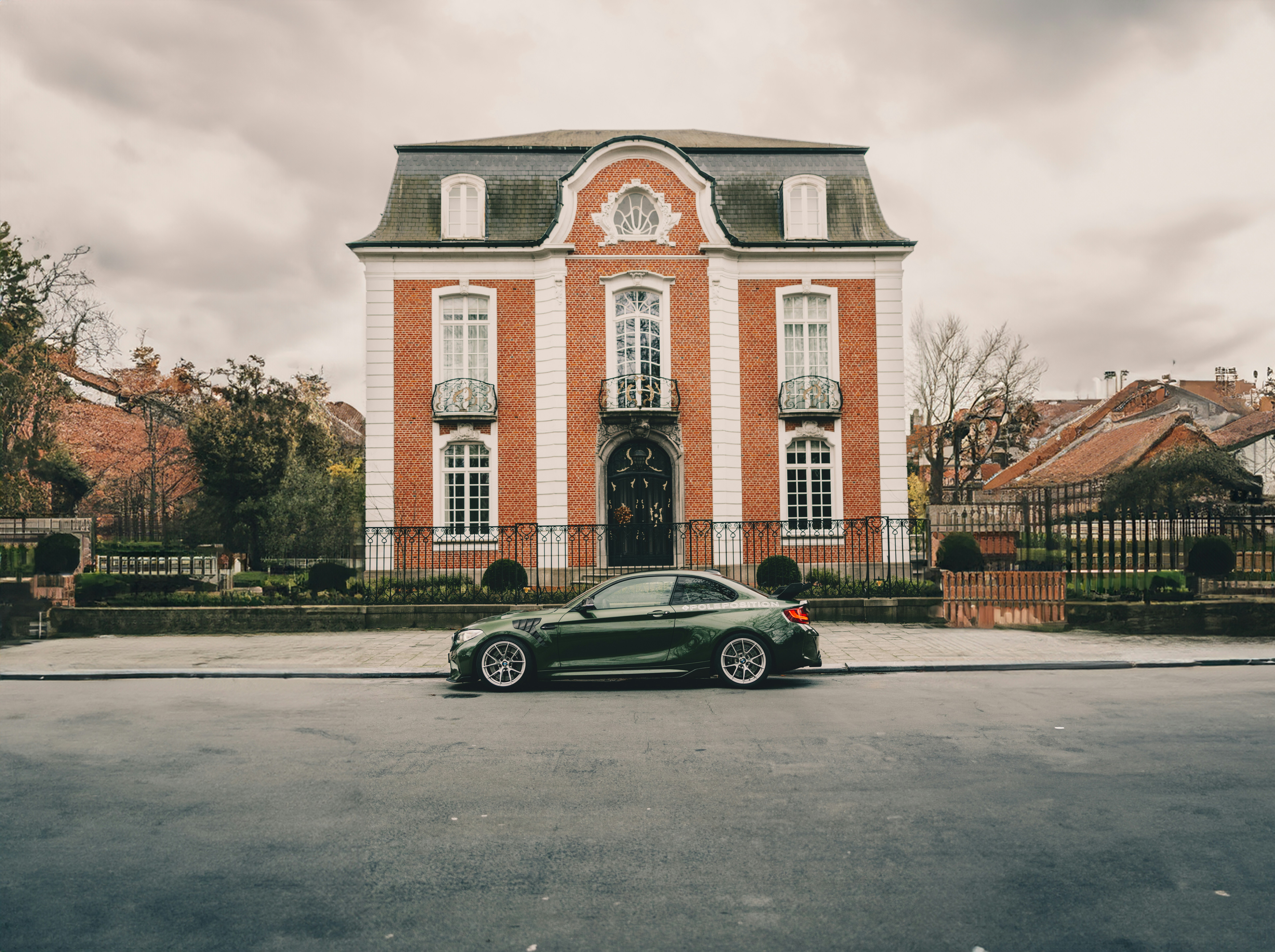 a green car parked in front of a red brick building
