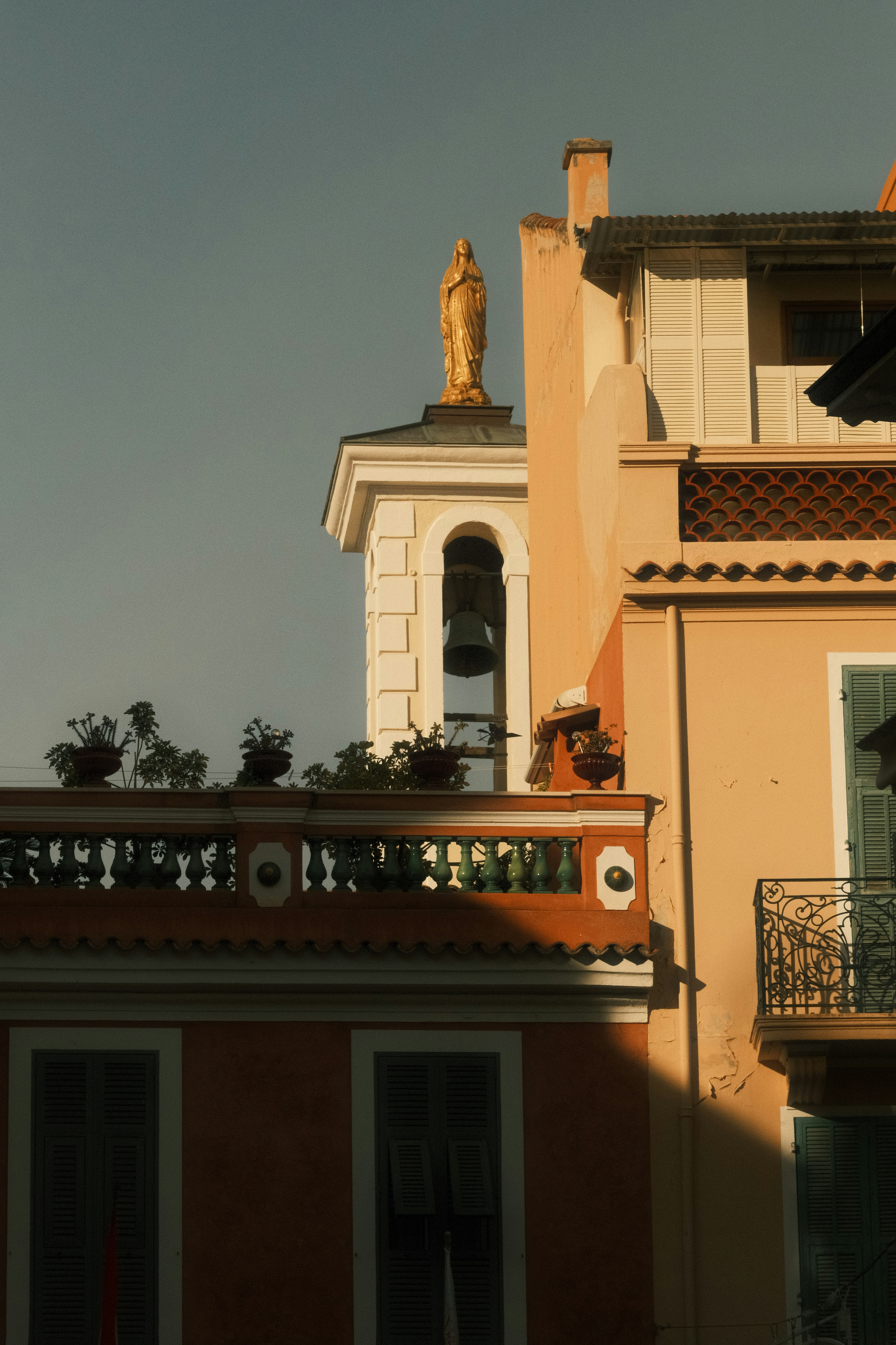 Golden Hour Bell Tower: A Stately Statue Over a Sunlit Mediterranean Terrace
