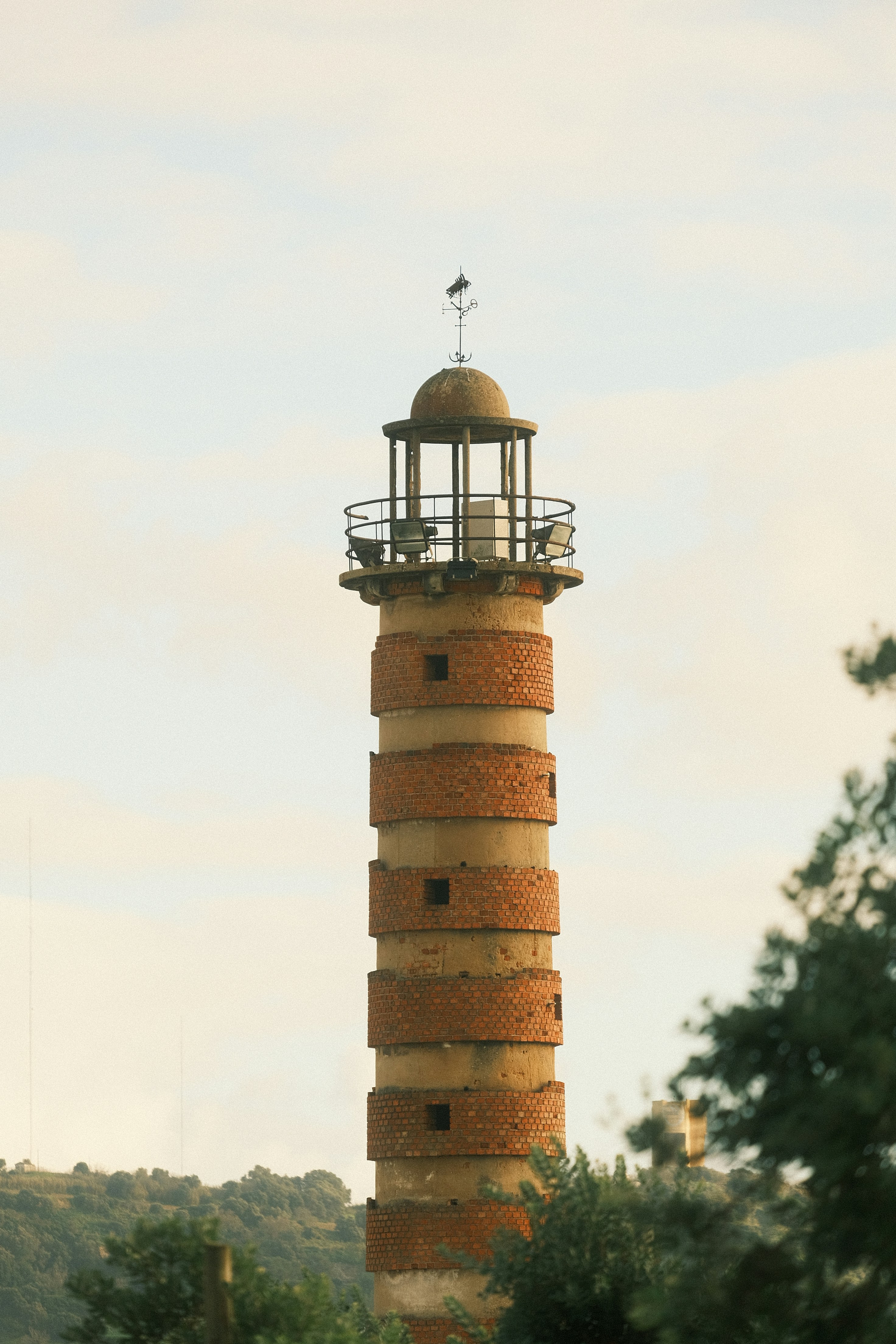 Brick Beacon with a Circular Gallery Rises Over a Quiet Coastal Landscape