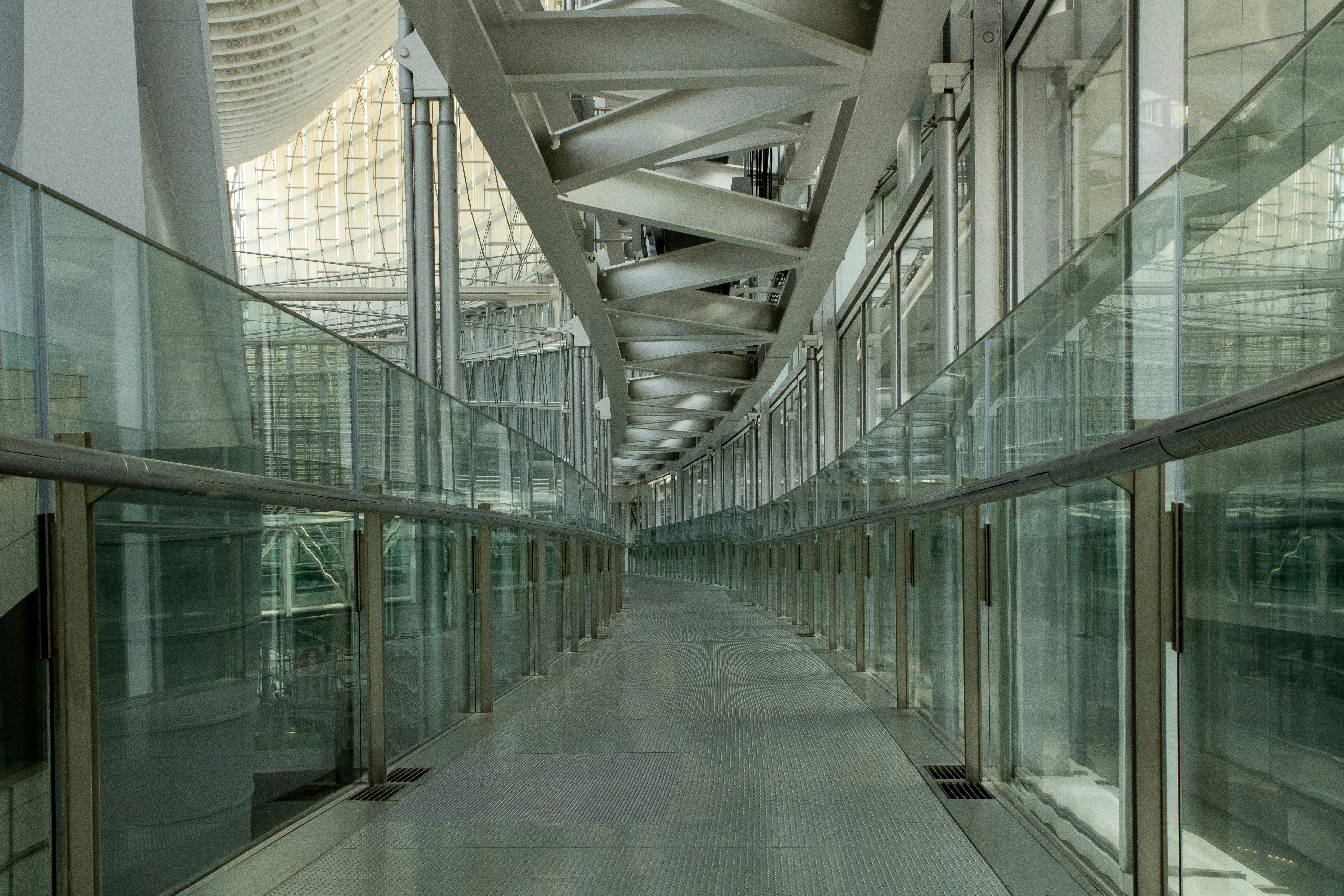 A long hallway with glass walls and metal railings photo – Free Grey ...