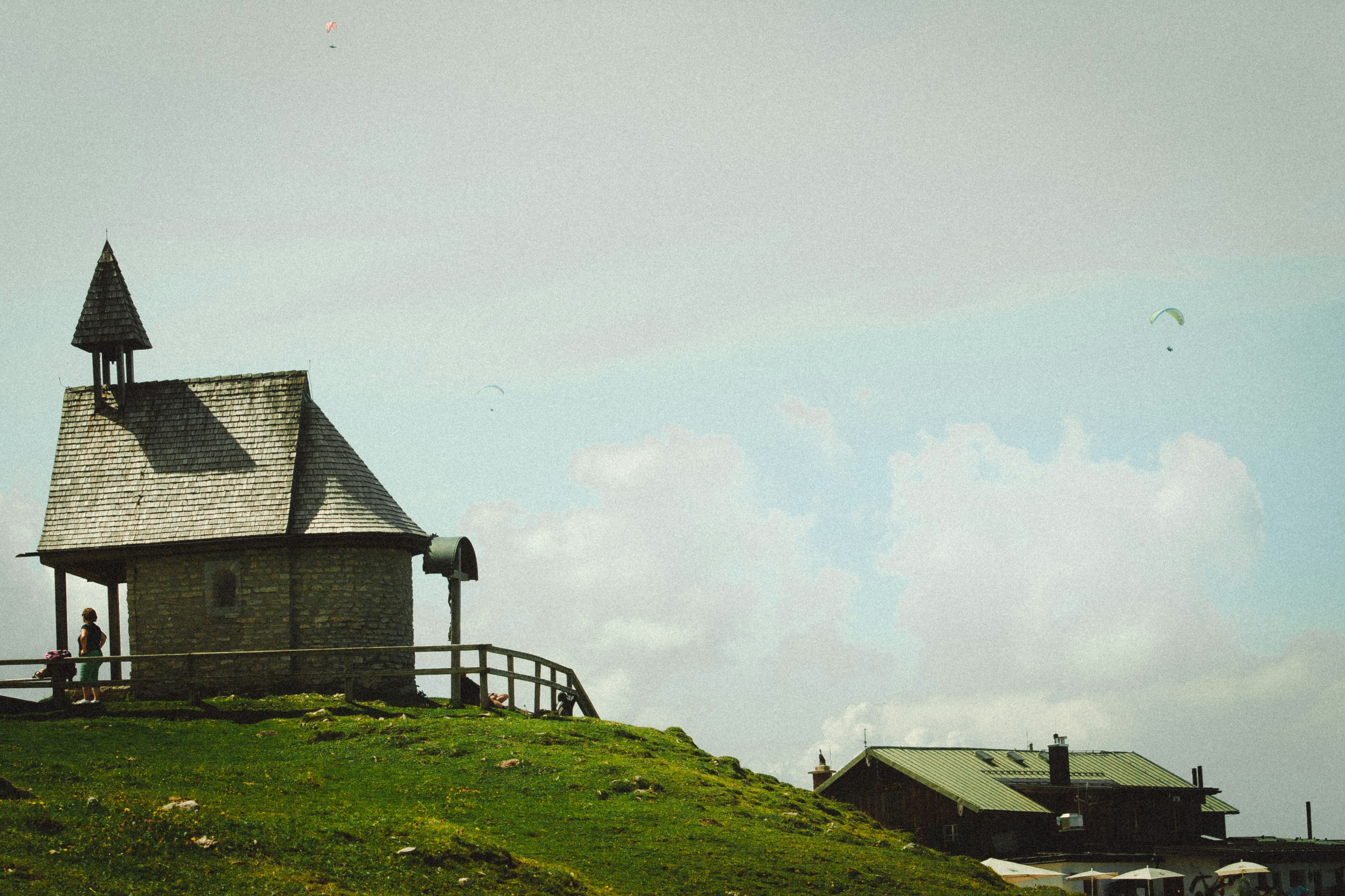 Timber Sentinel on a Green Crest Overlooking a Quiet Coastal Settlement