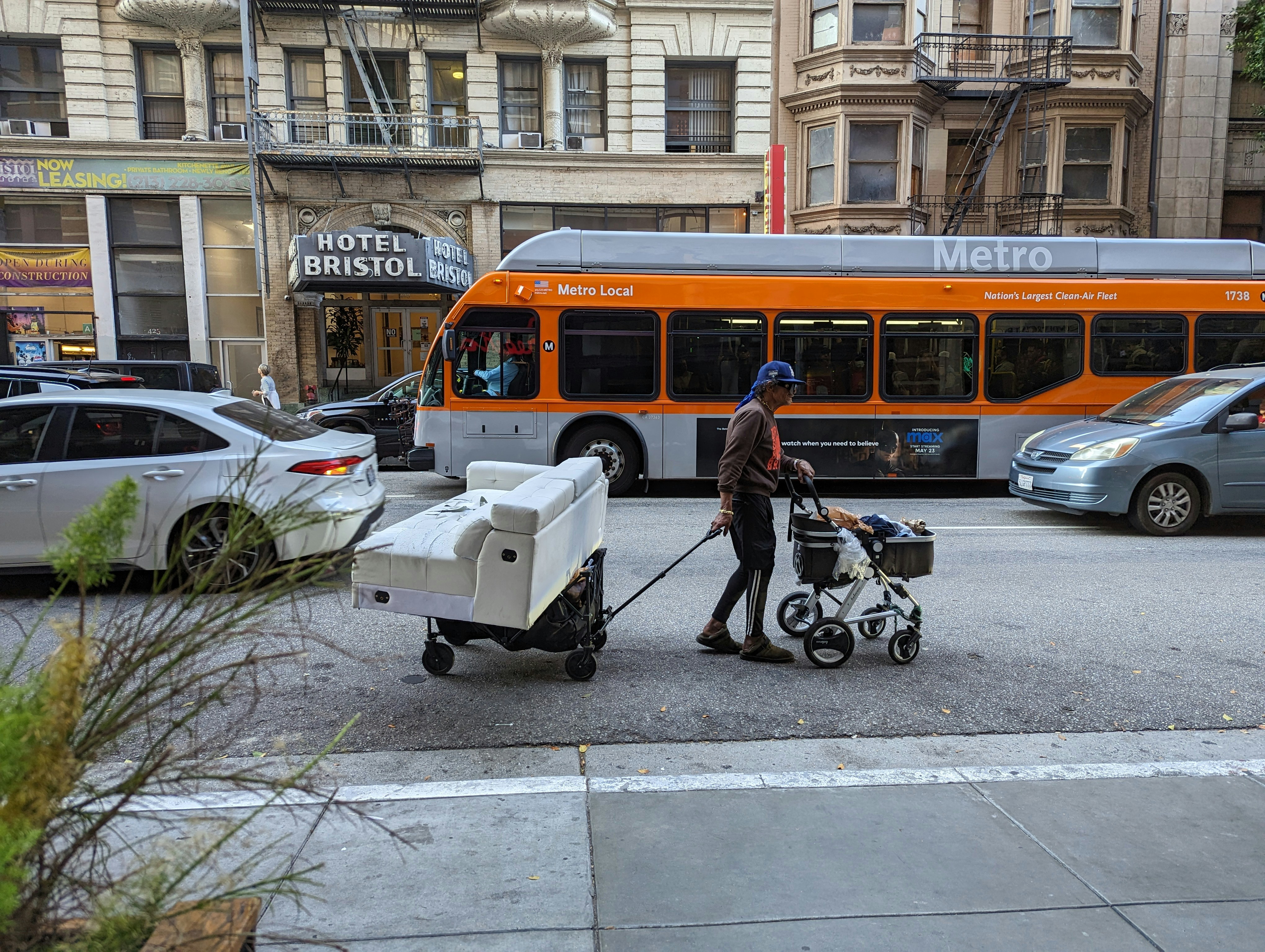 A woman pushing a stroller next to a bus photo – Free Street Image on ...