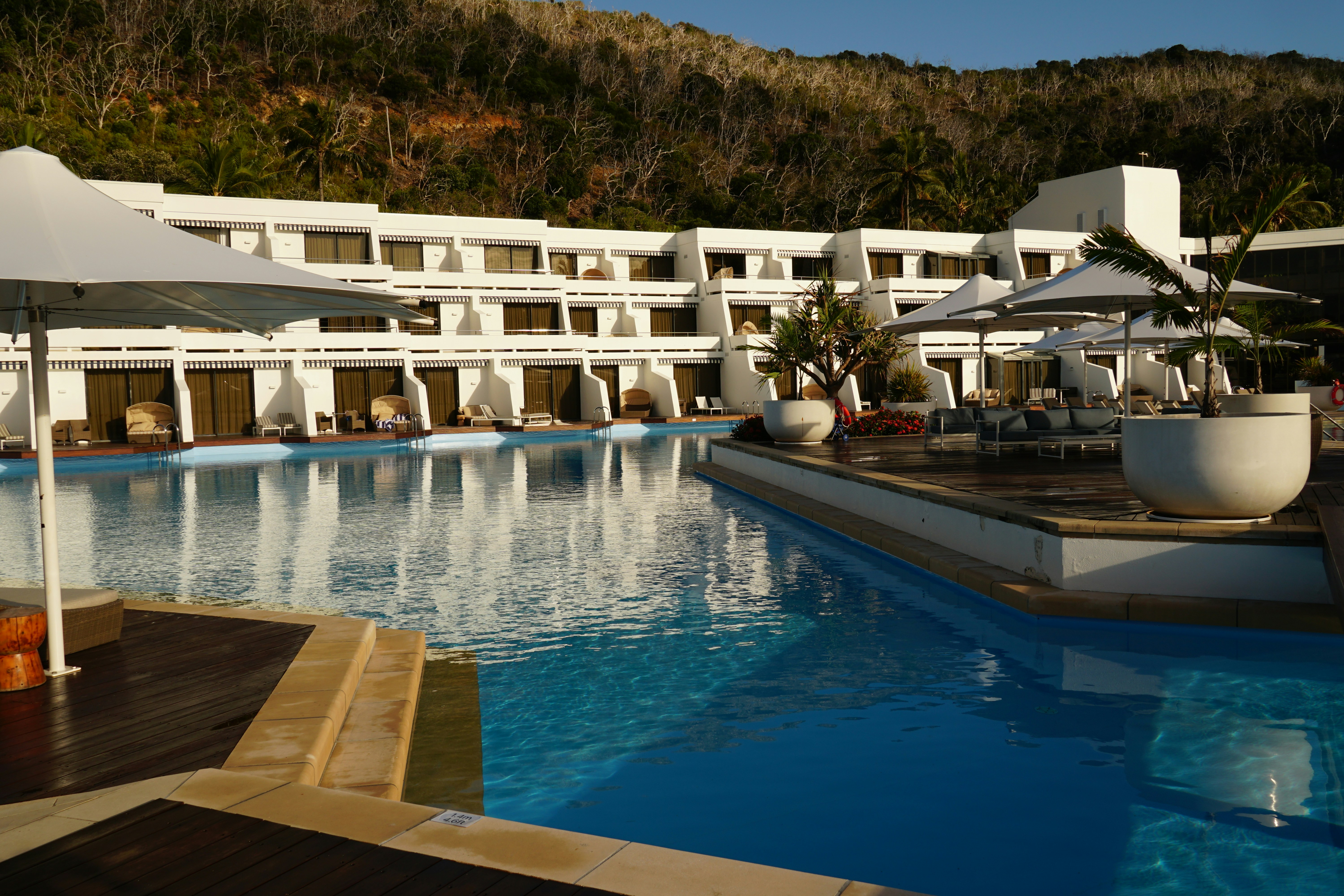 A hotel with a large swimming pool surrounded by umbrellas photo – Free ...