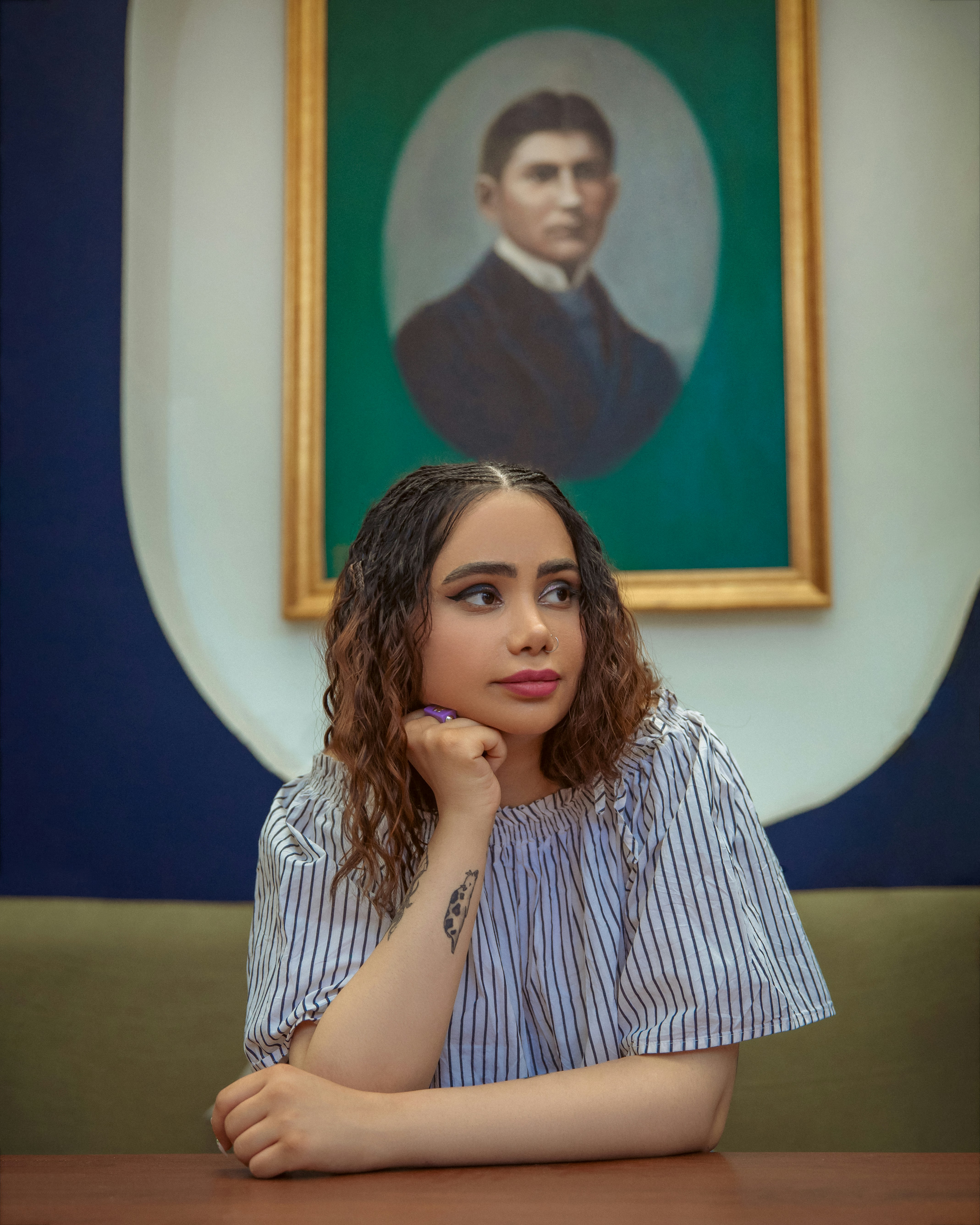 Thoughtful Gaze Beneath a Portrait: A Quiet Moment at the Table