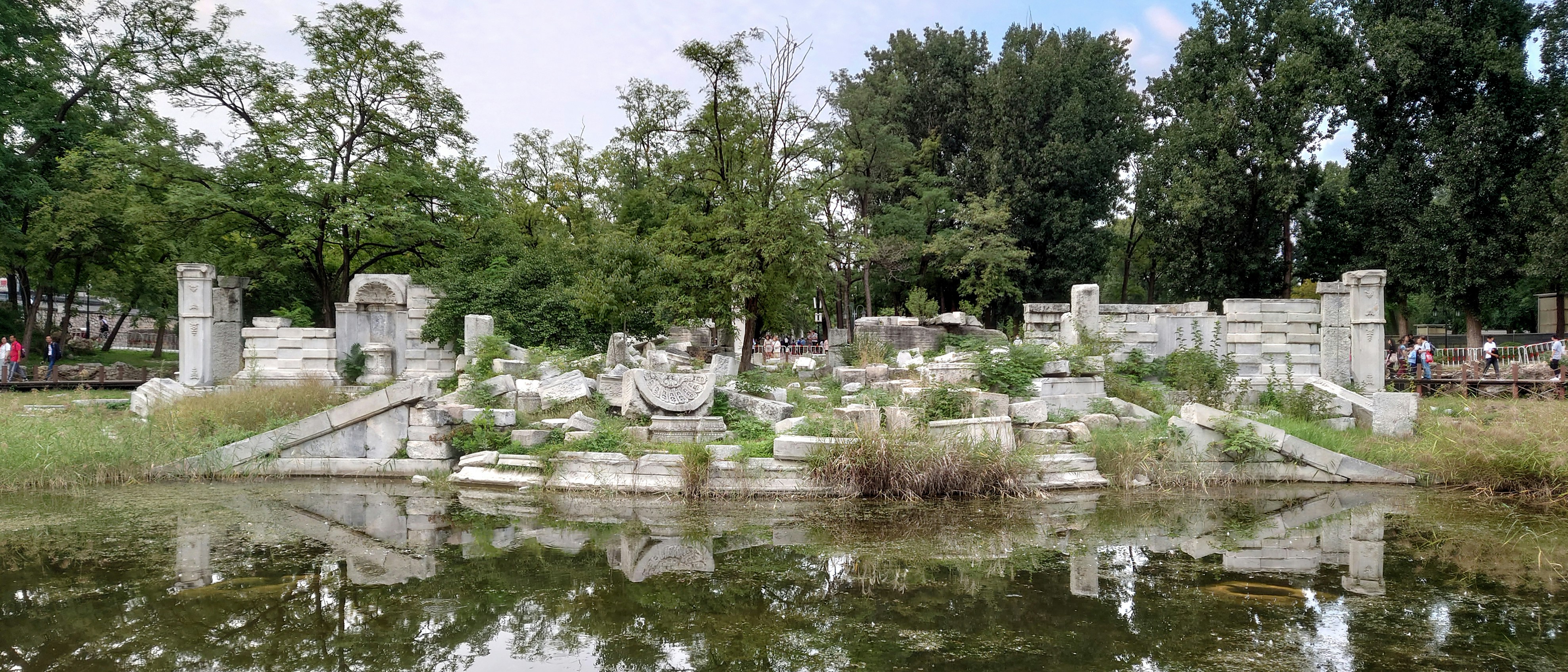 Ruinous terrace in a tranquil park reflecting in still water