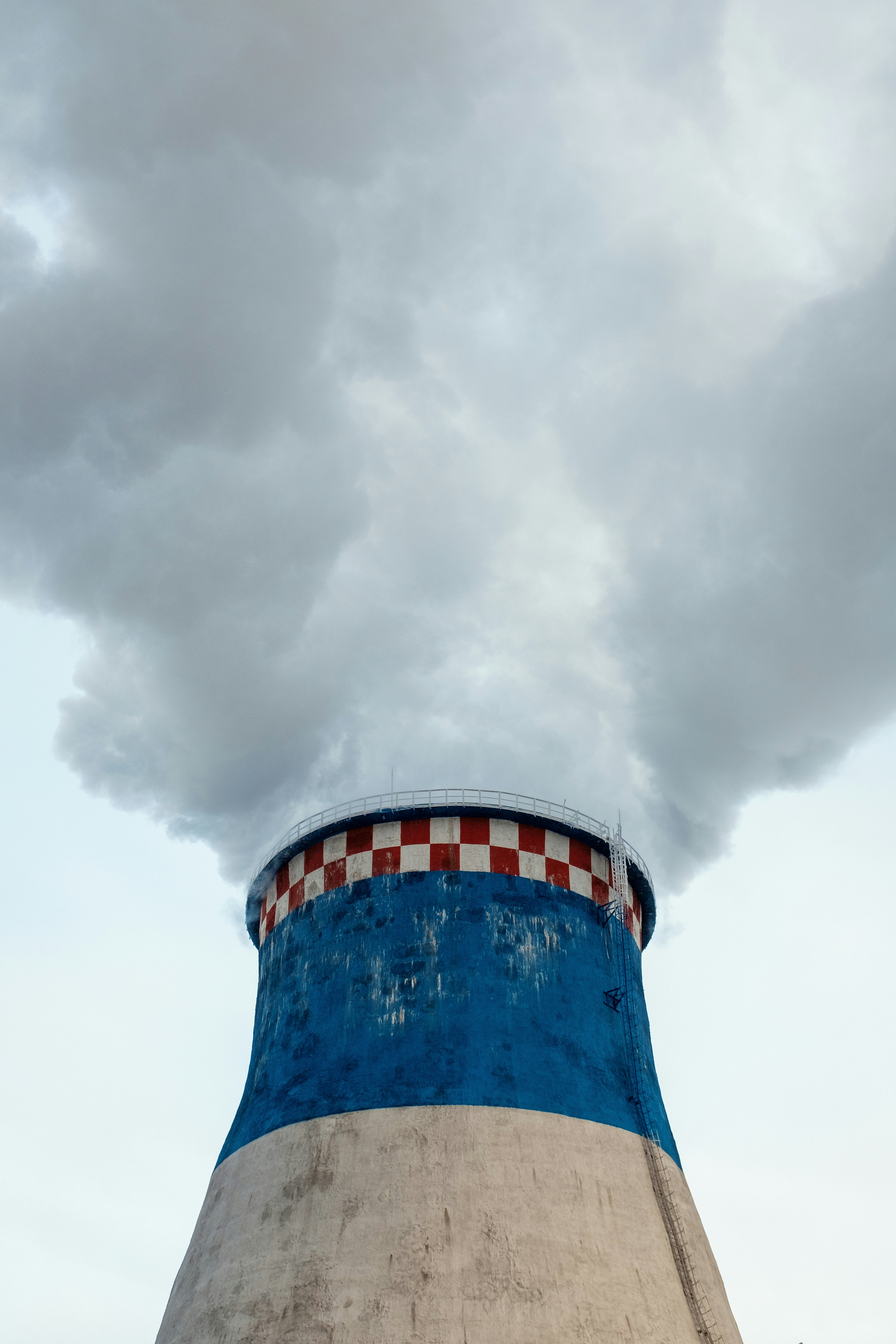 Checkered Crown Cooling Tower Breathing Steam into a Pale Sky