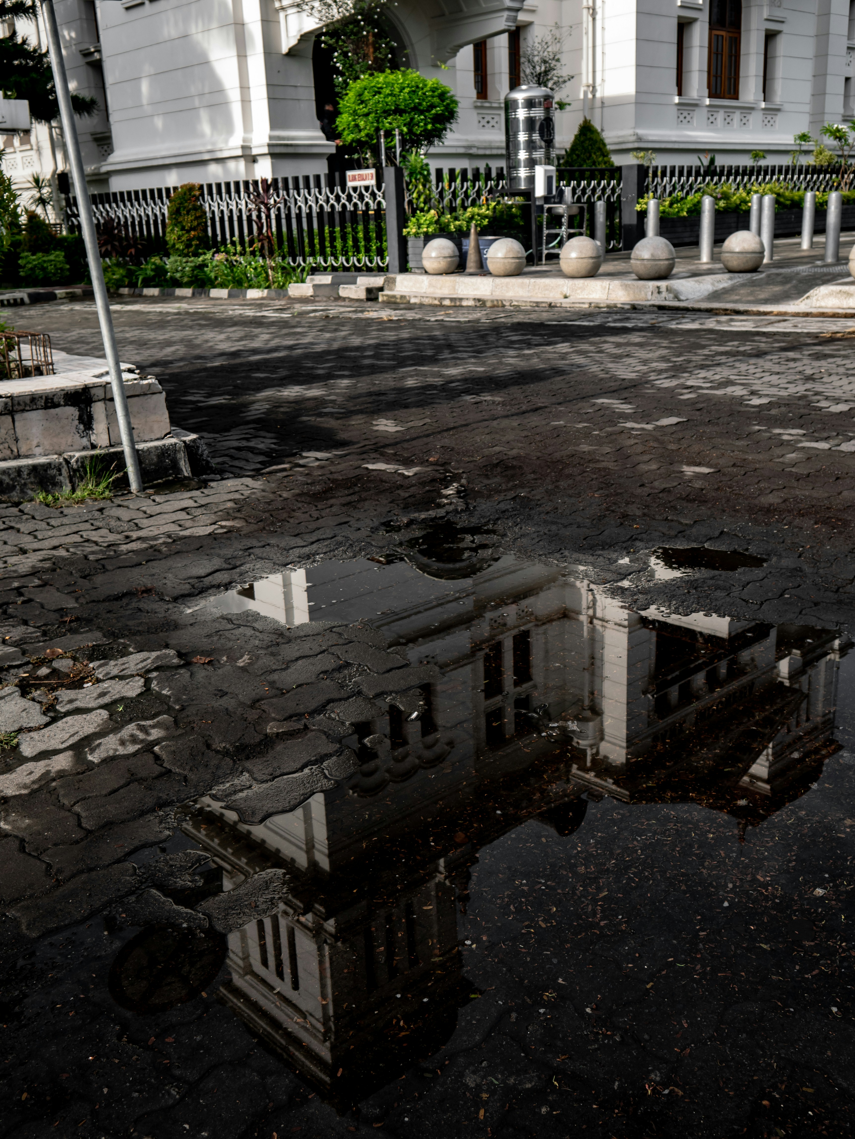 Reflected Facade: White Architecture Reborn in a Rain-Slick Puddle