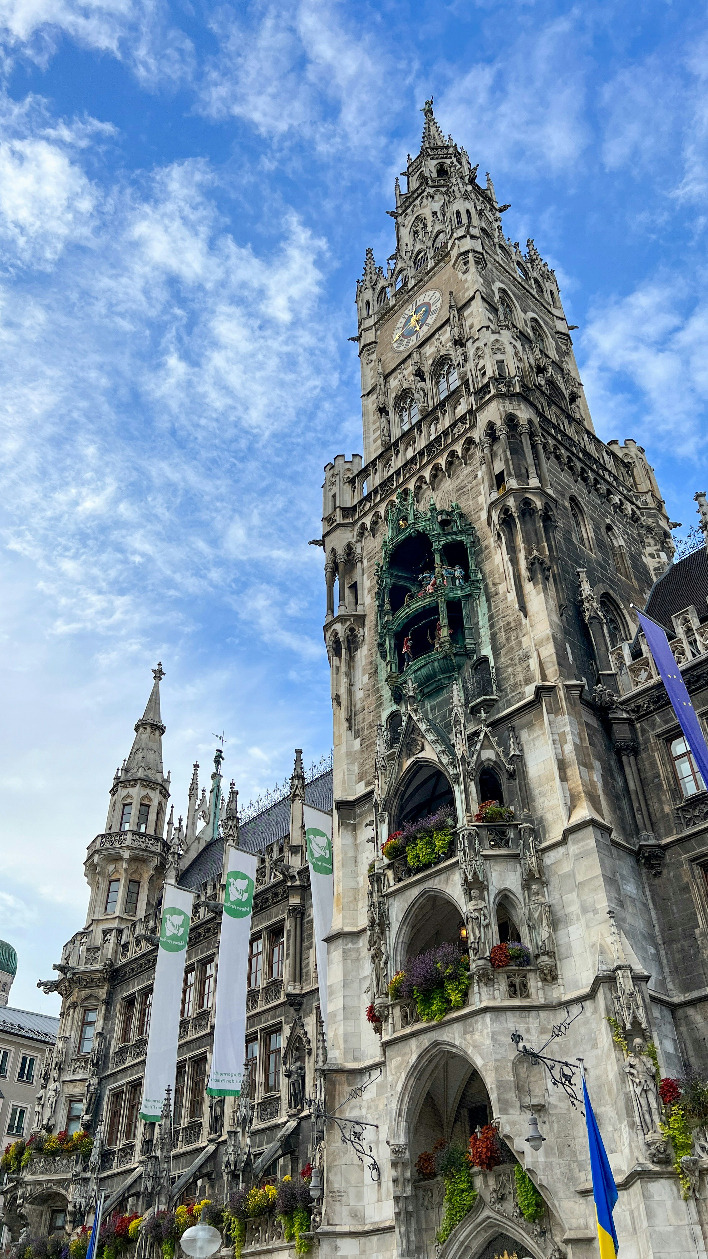 Skyward Gothic: The Clock Tower Framed by Flags and Flowers