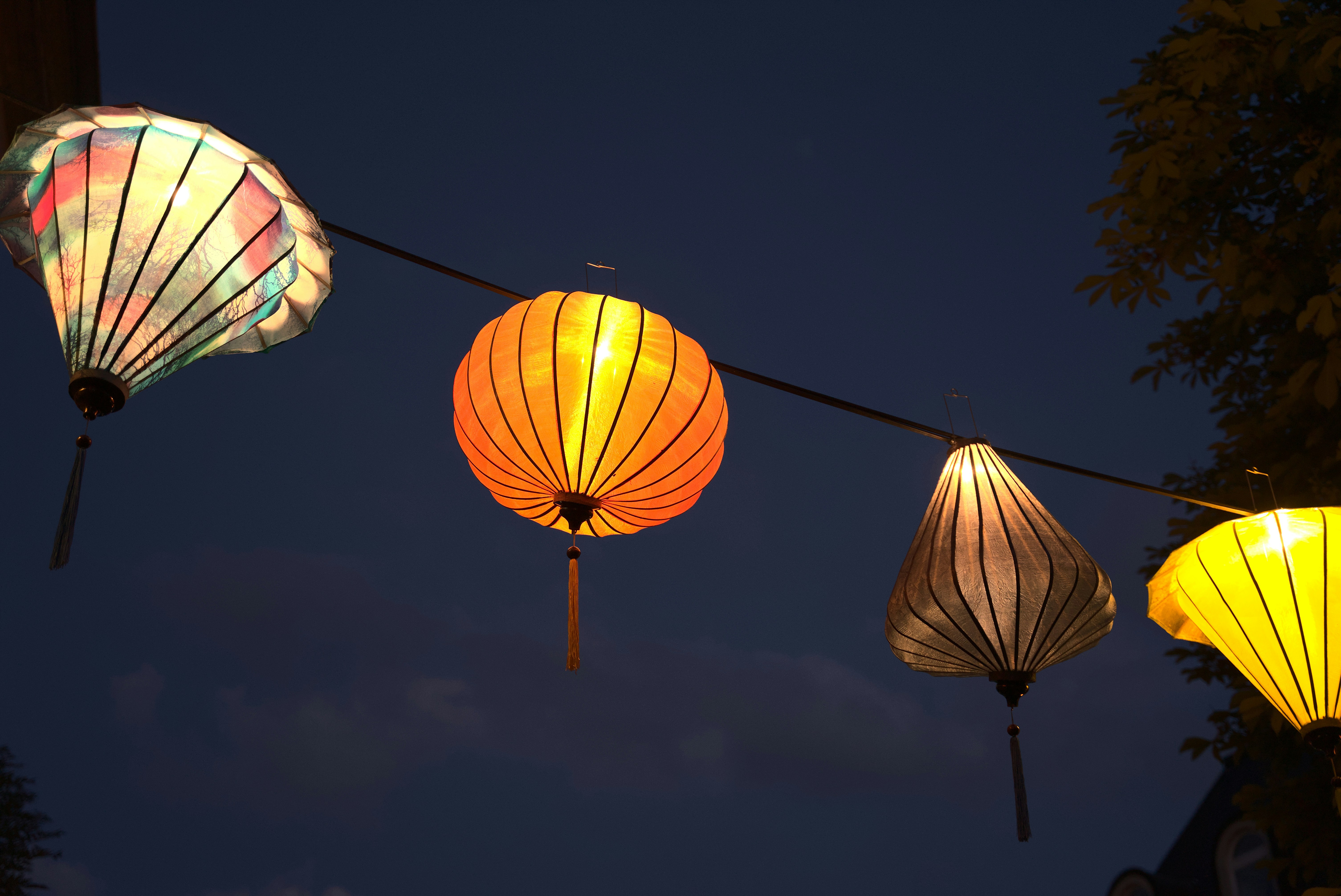 A string of colorful lanterns hanging from a tree photo – Free ...