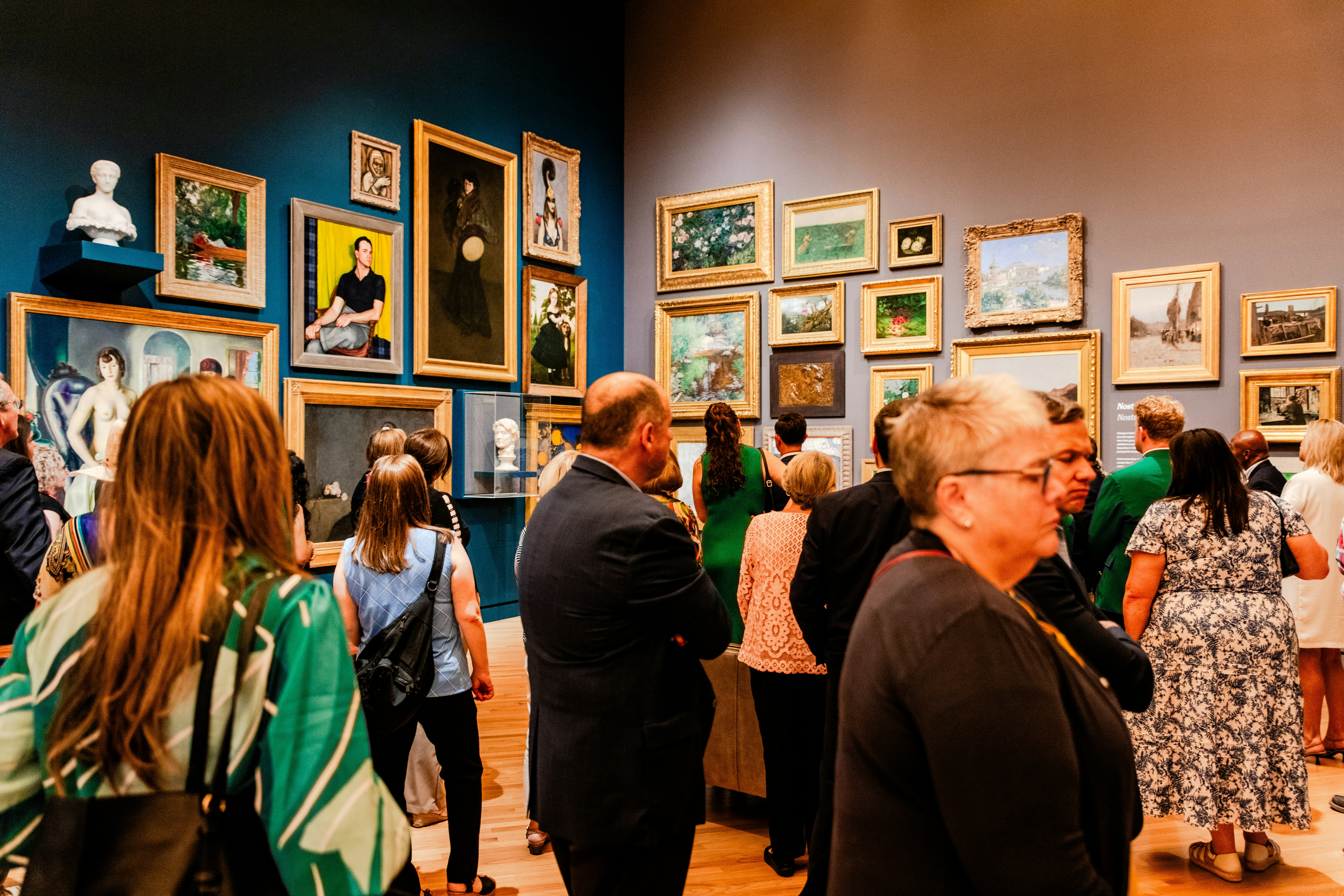 A group of people standing in a museum looking at pictures photo – Free ...