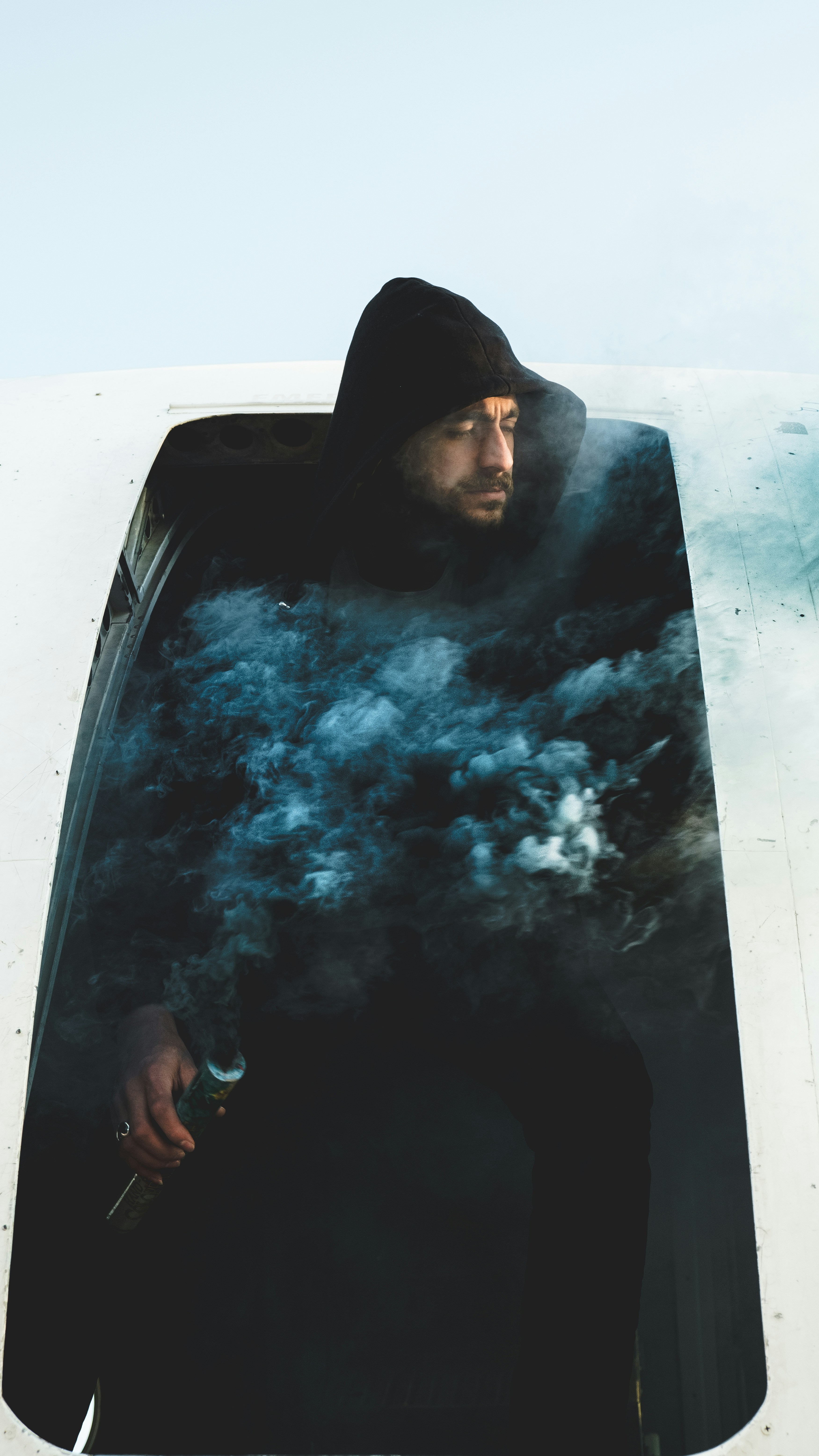 Smoke and Hood: A man emerging from the cockpit with vape and mystery