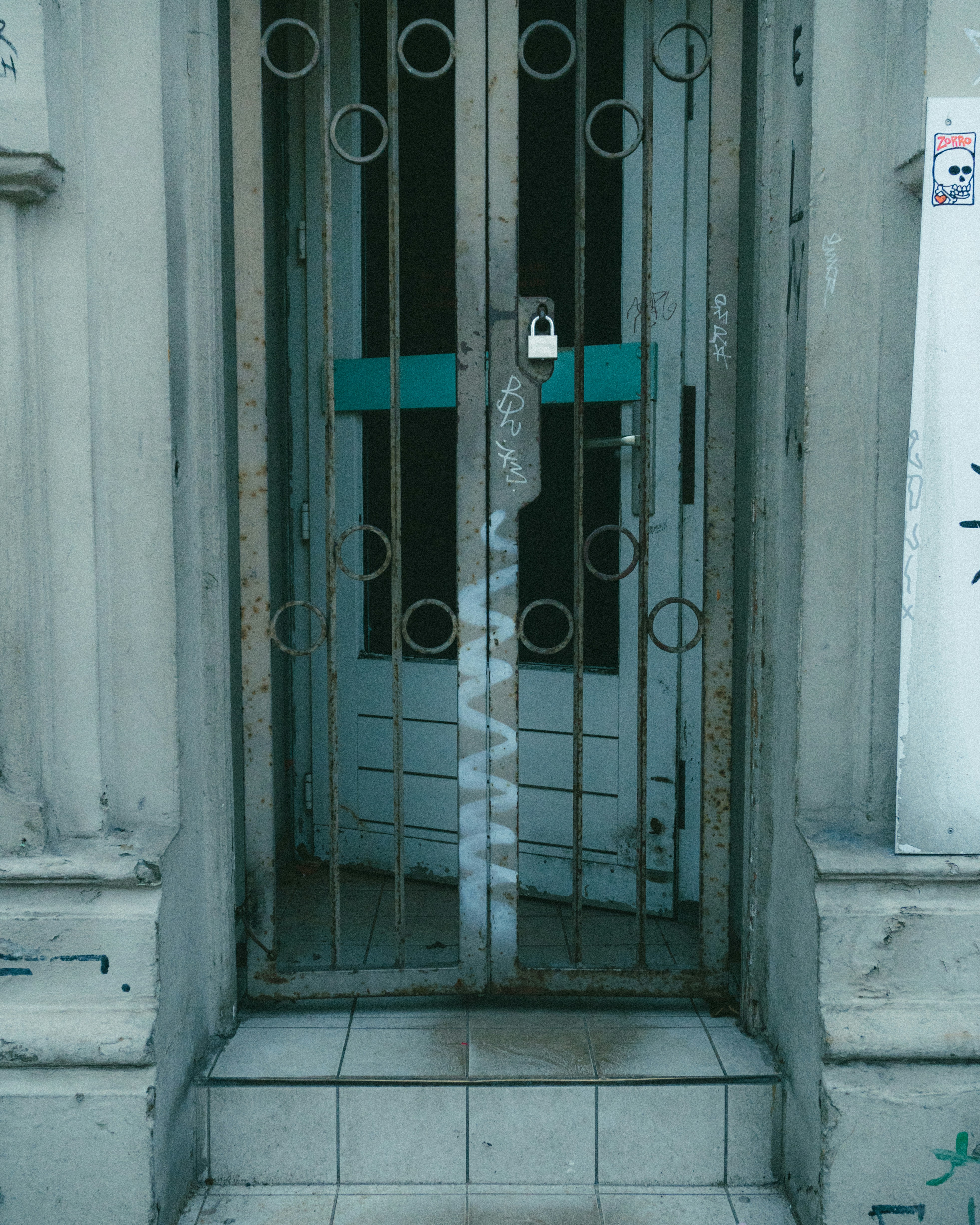 Locked Gate, Teal Bar: A Weathered Doorway's Quiet Resolve