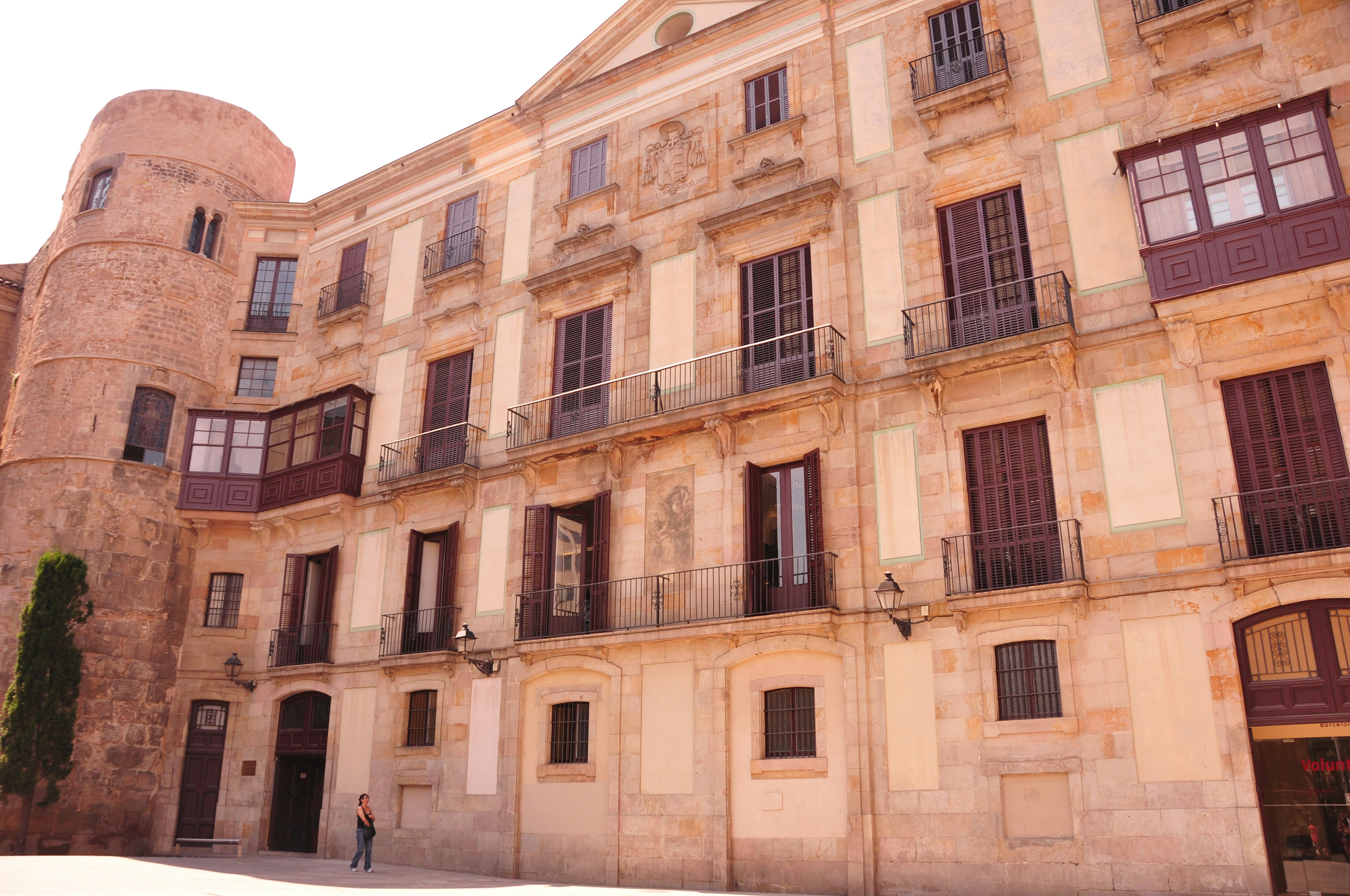 Stone building with arched windows and a cylindrical tower in bright daylight.