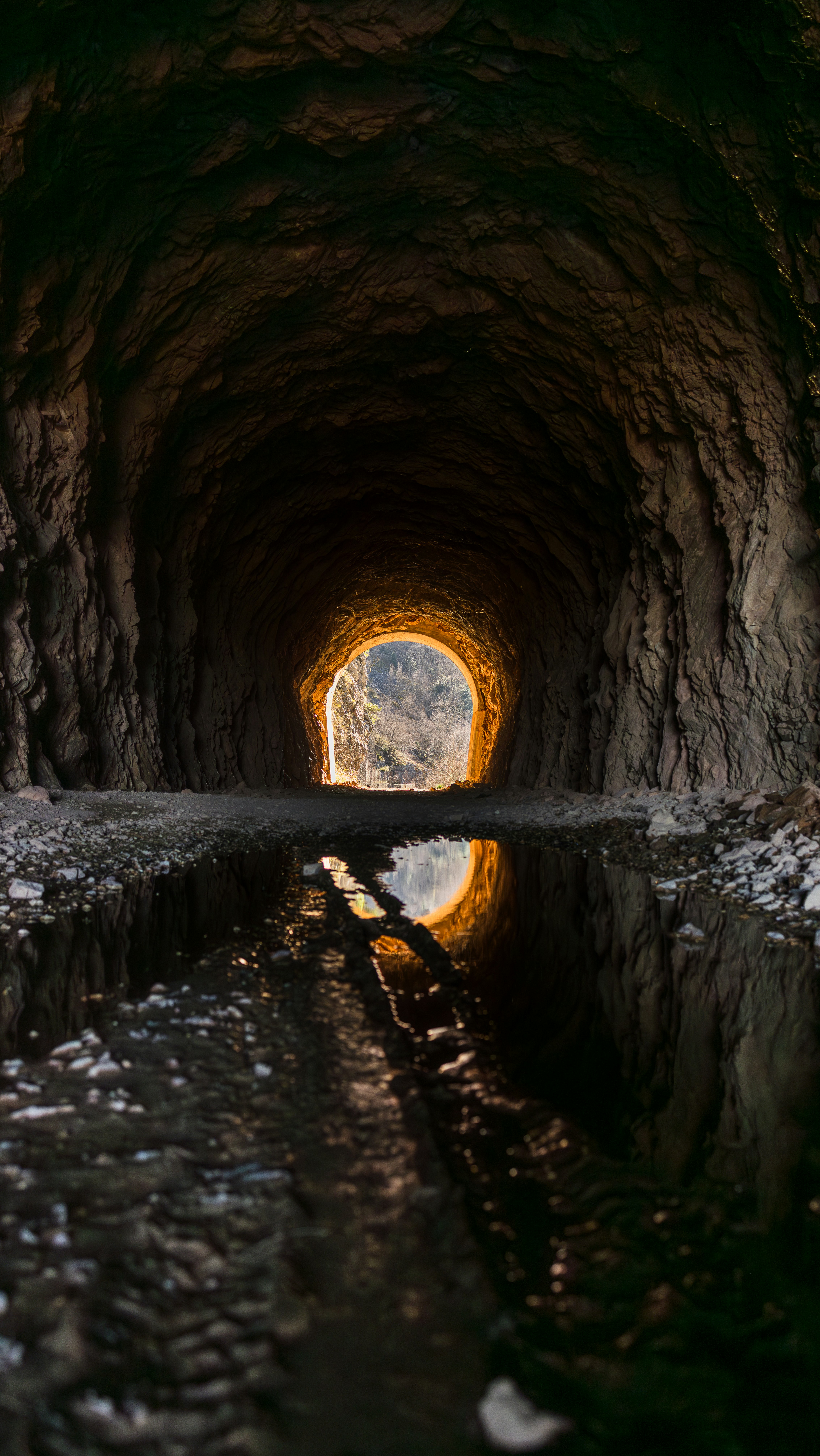 Circular Portal at Tunnel’s End: Light Framing a Rock-Walled Corridor