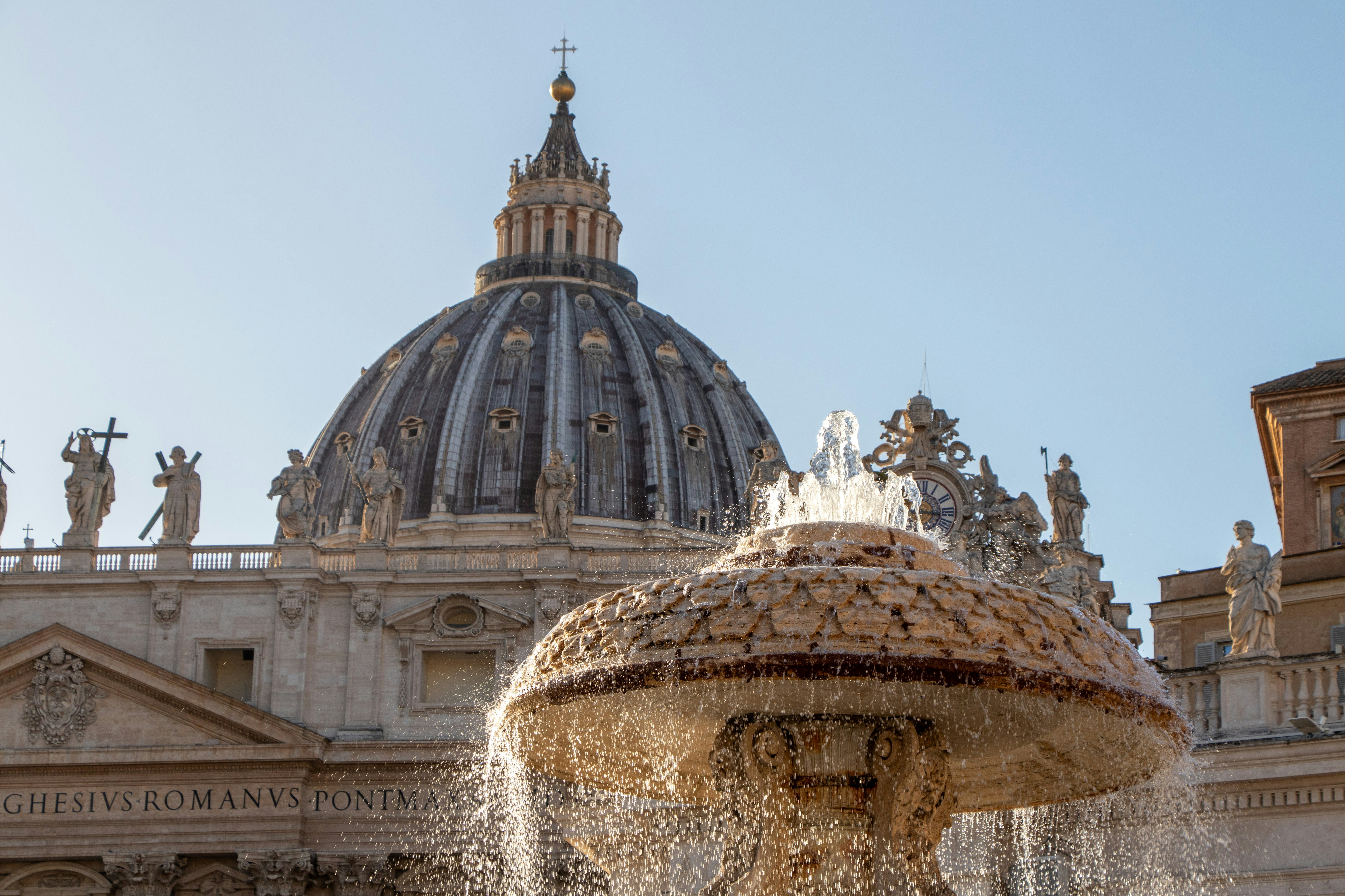 Fountain cascading in front of an ornate domed building under a clear sky.
