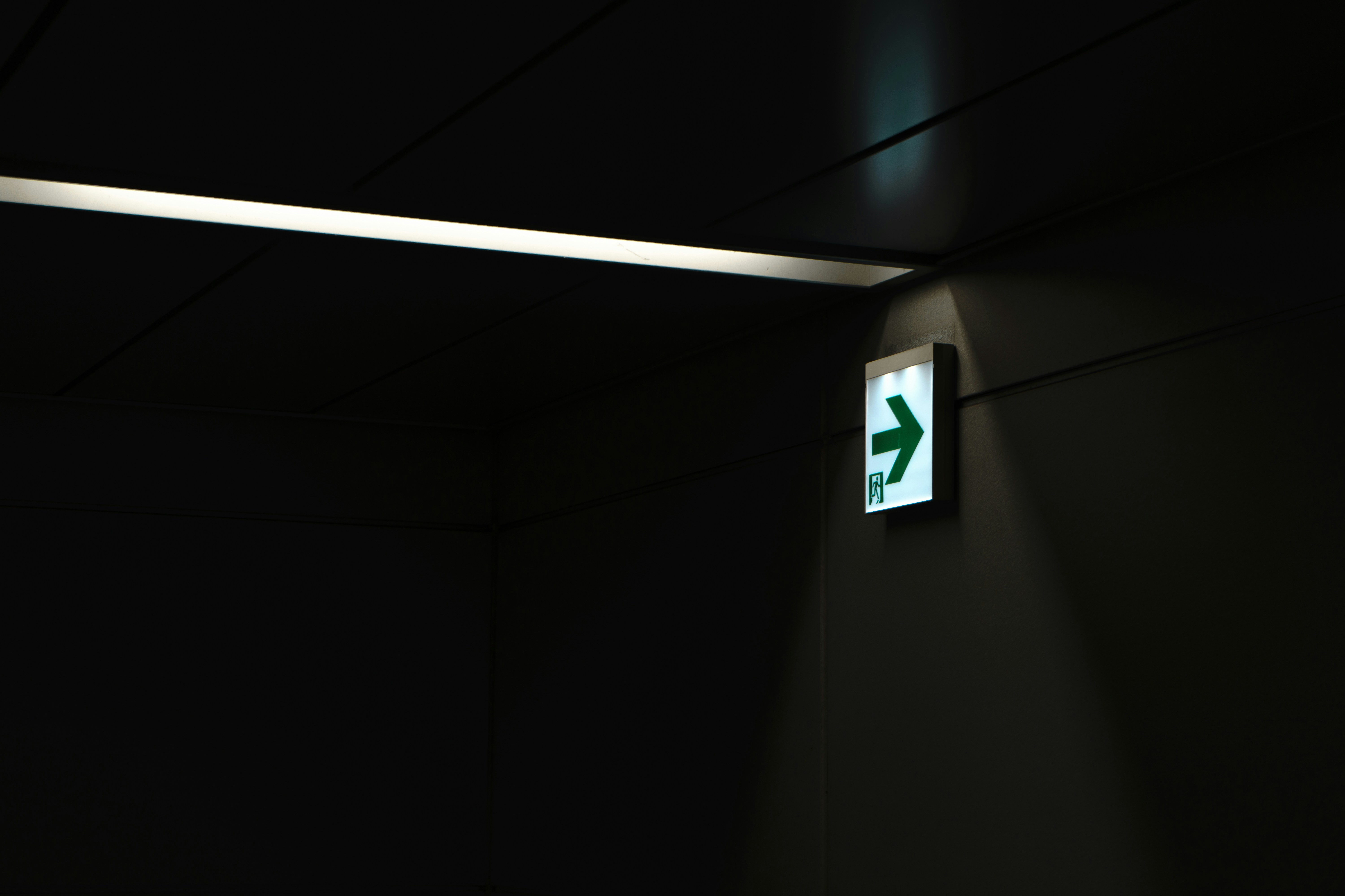 Dimly lit corridor with an illuminated green exit sign casting a glow.