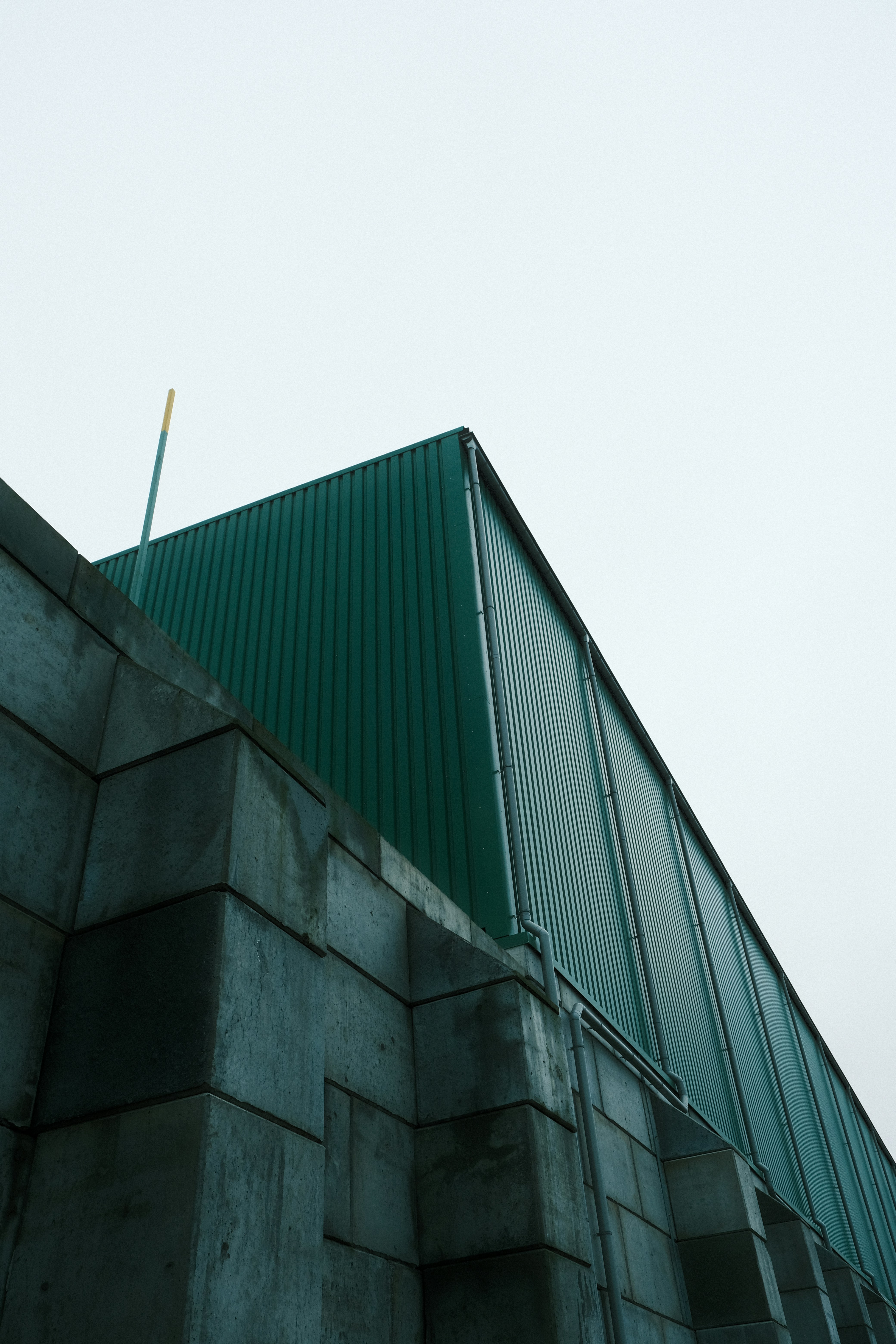 A building with a green roof next to a wall photo – Free Energy Image ...