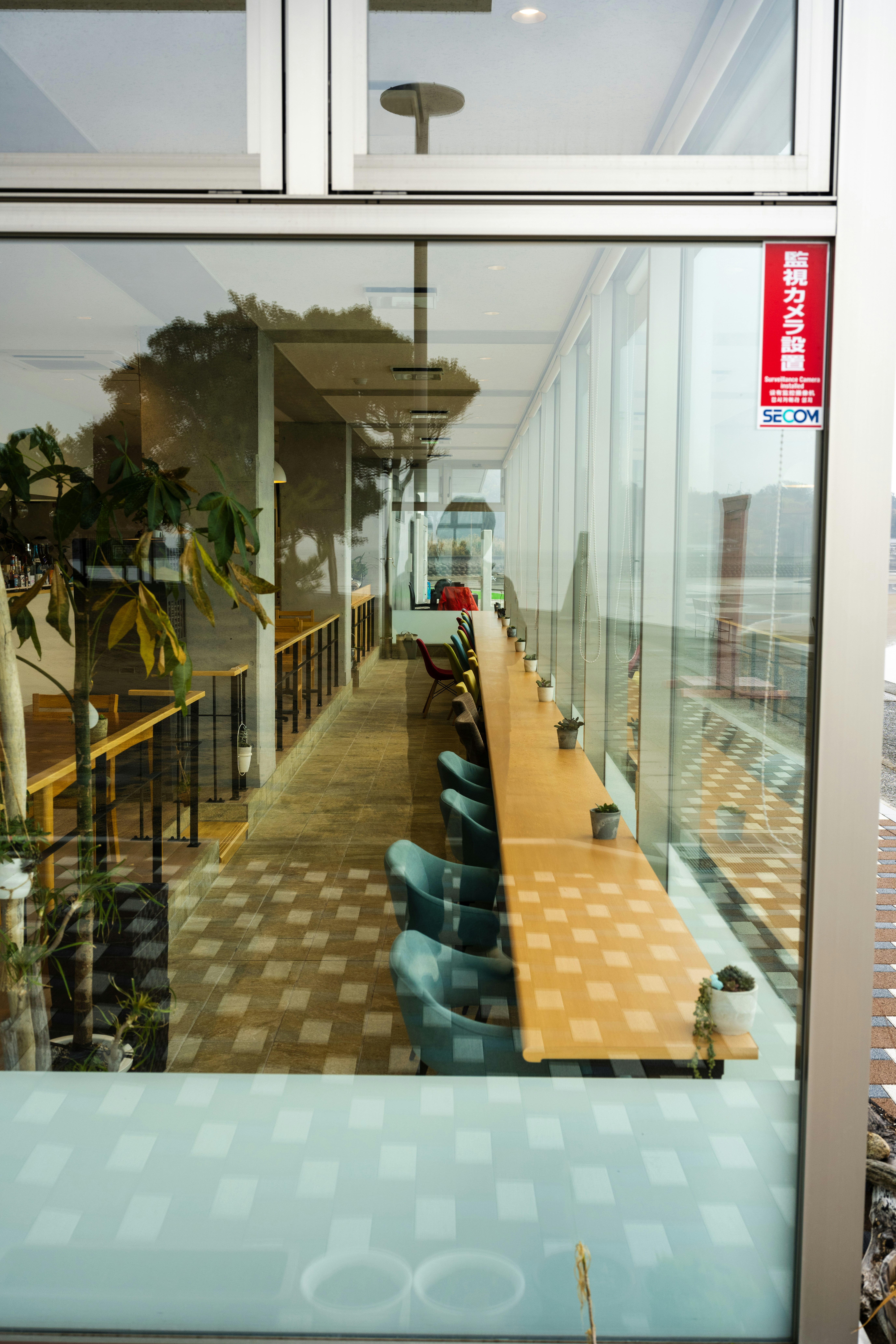 Red Figure at the End of a Glass-Walled Café Corridor