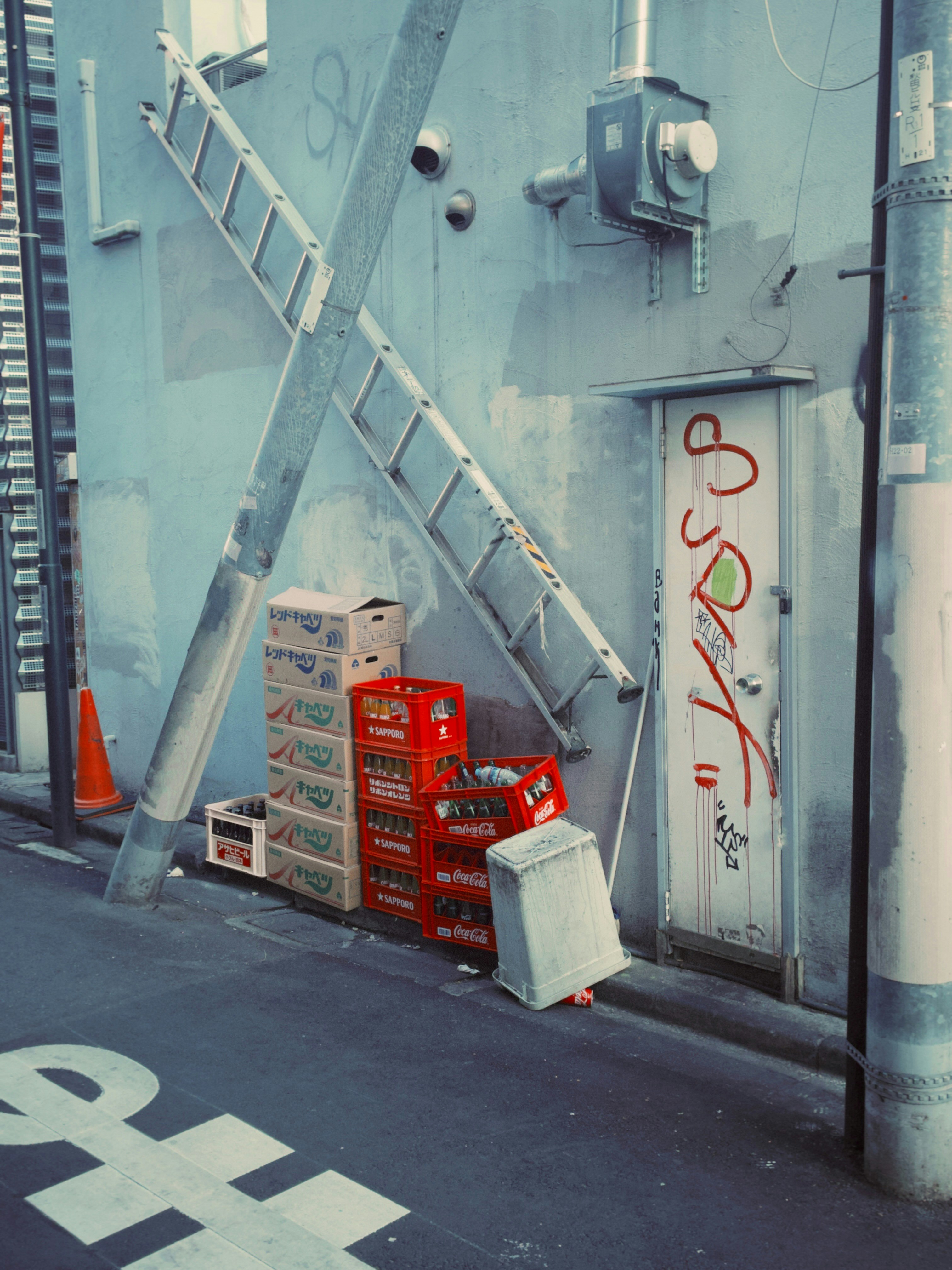 Diagonal Ladder Over Stacked Crates in a Blue-Gray Alley