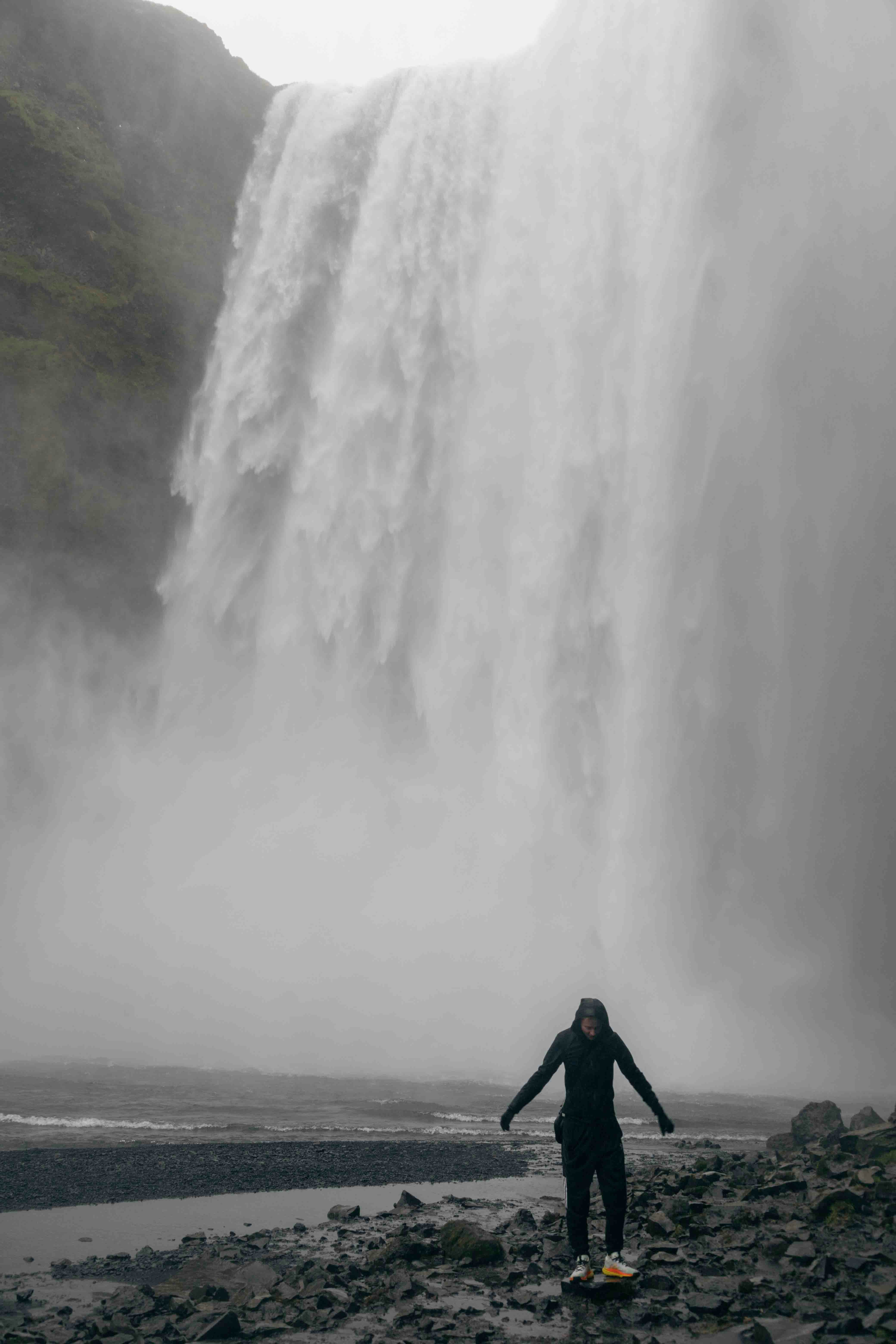 Mist at the Foot of the Curtain: A lone figure stands before a colossal waterfall