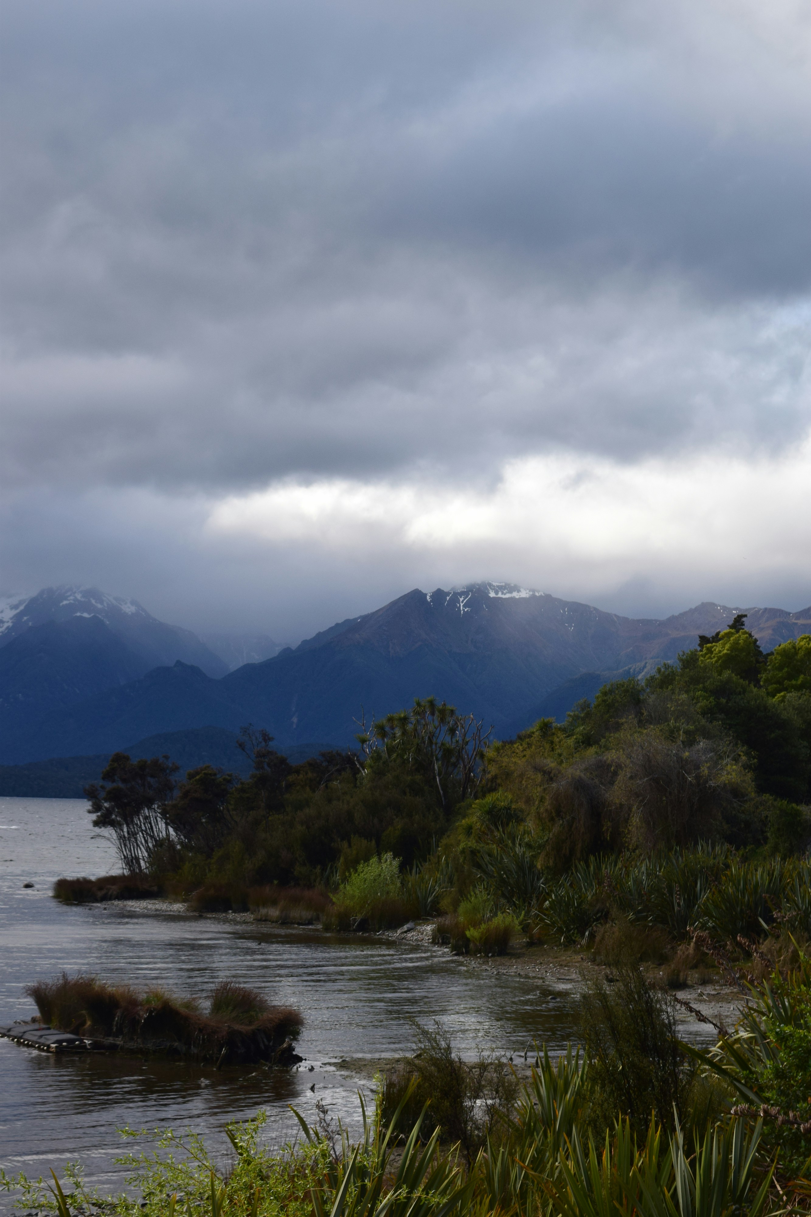 Shoreline silhouettes under brooding mountain skies