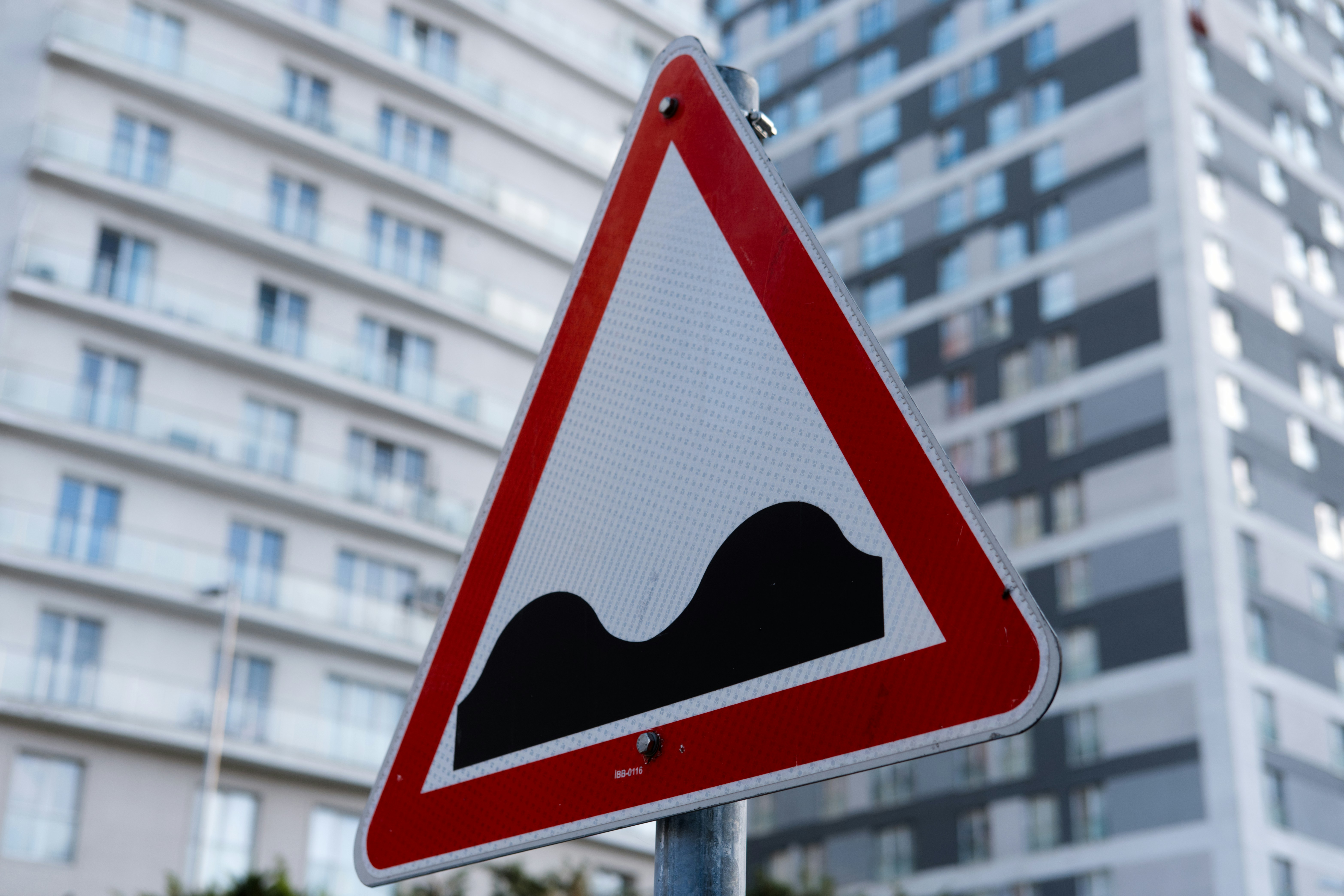 A red and white triangular sign in front of a tall building photo ...